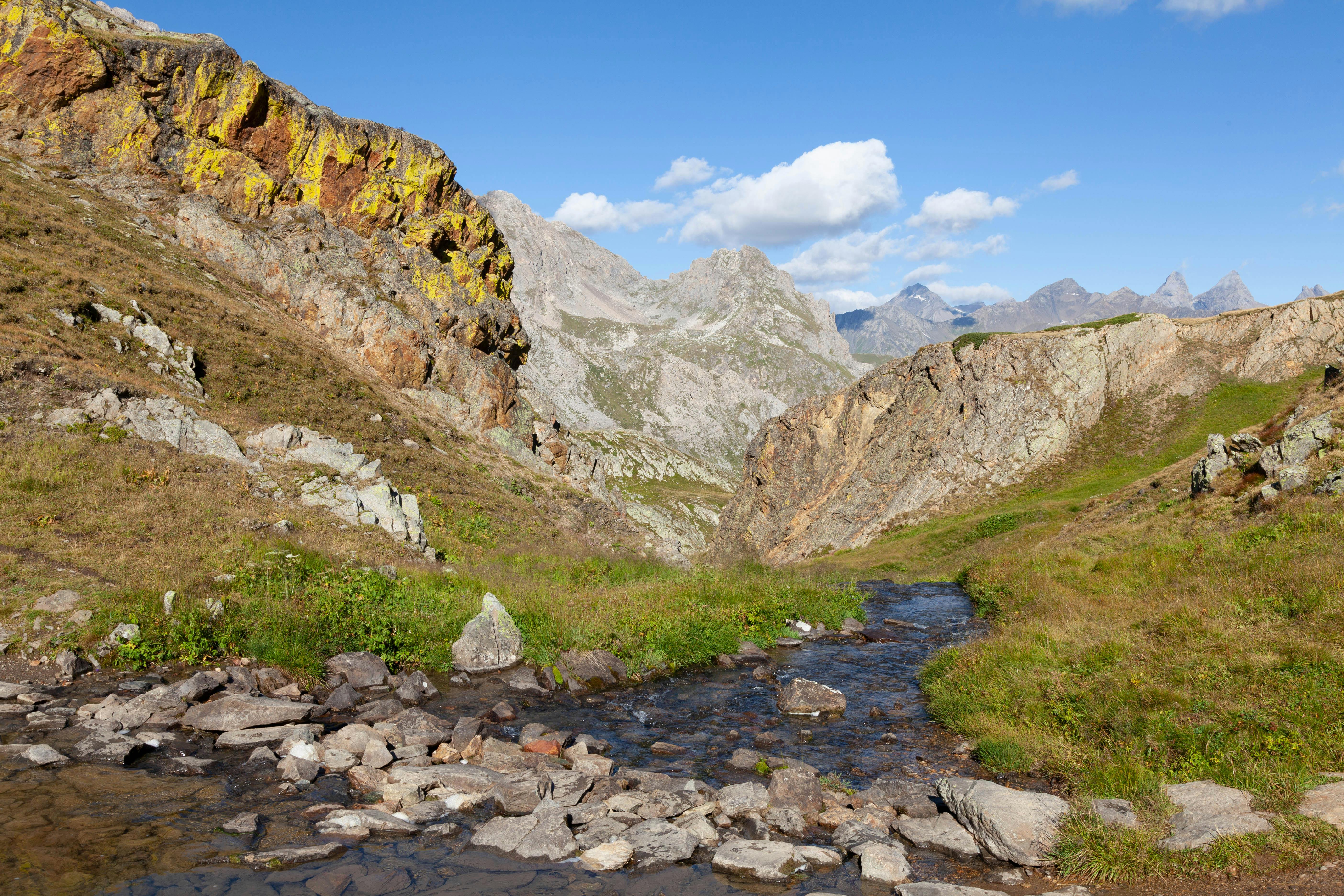 A stream runs through a rocky valley in the mountains · Free Stock Photo