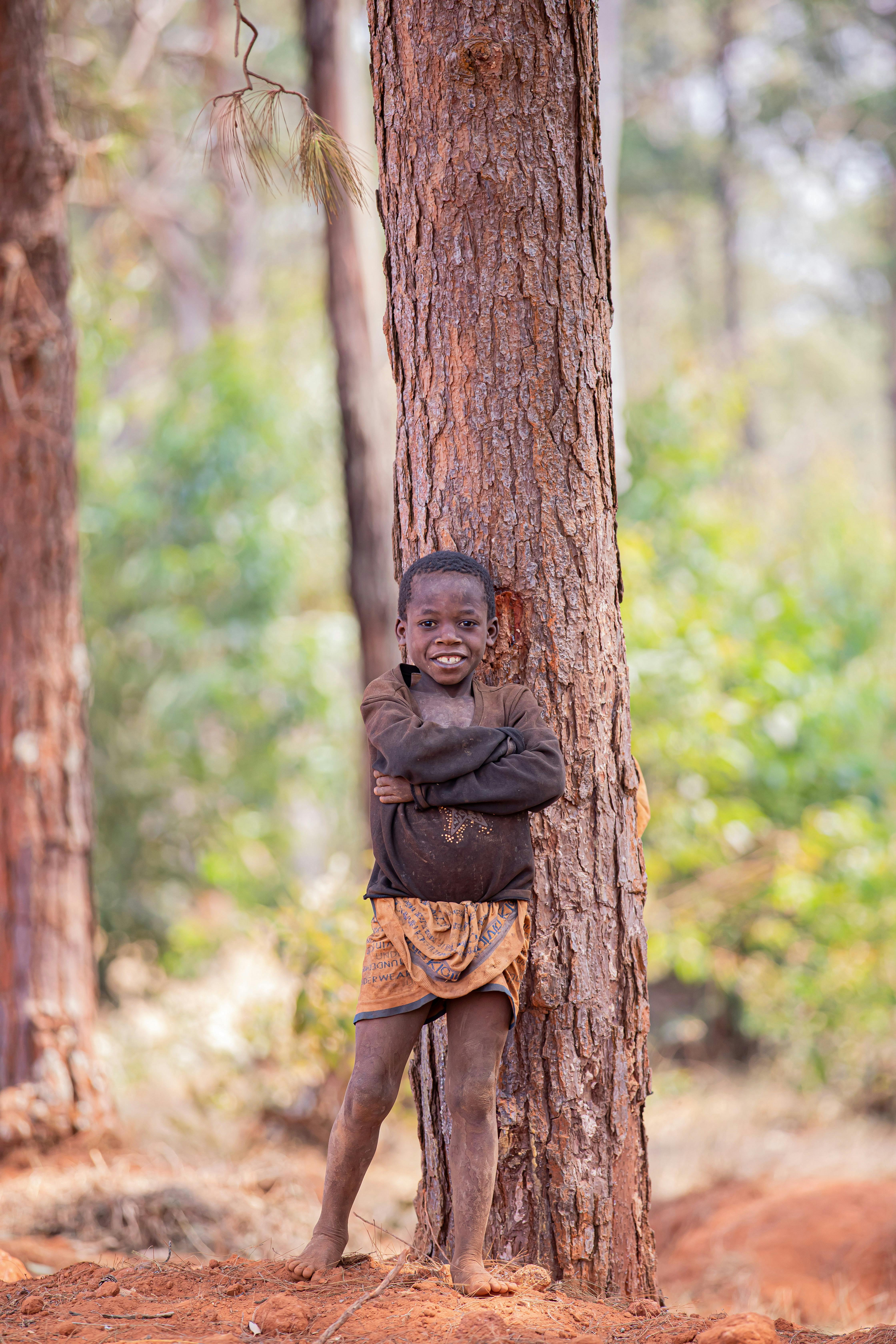 Smiling Boy Standing by Tree · Free Stock Photo