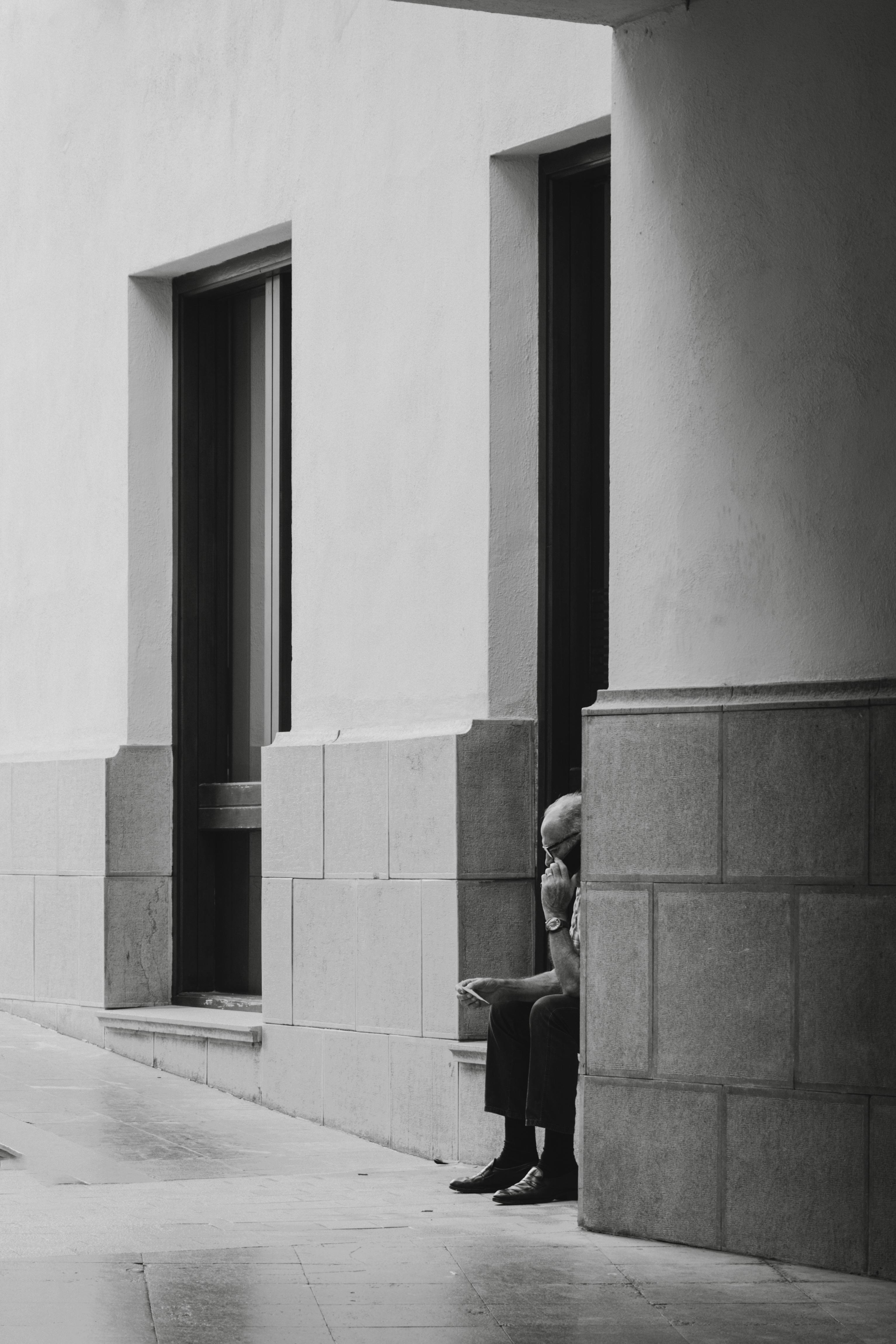 Man Sitting behind Building Wall · Free Stock Photo