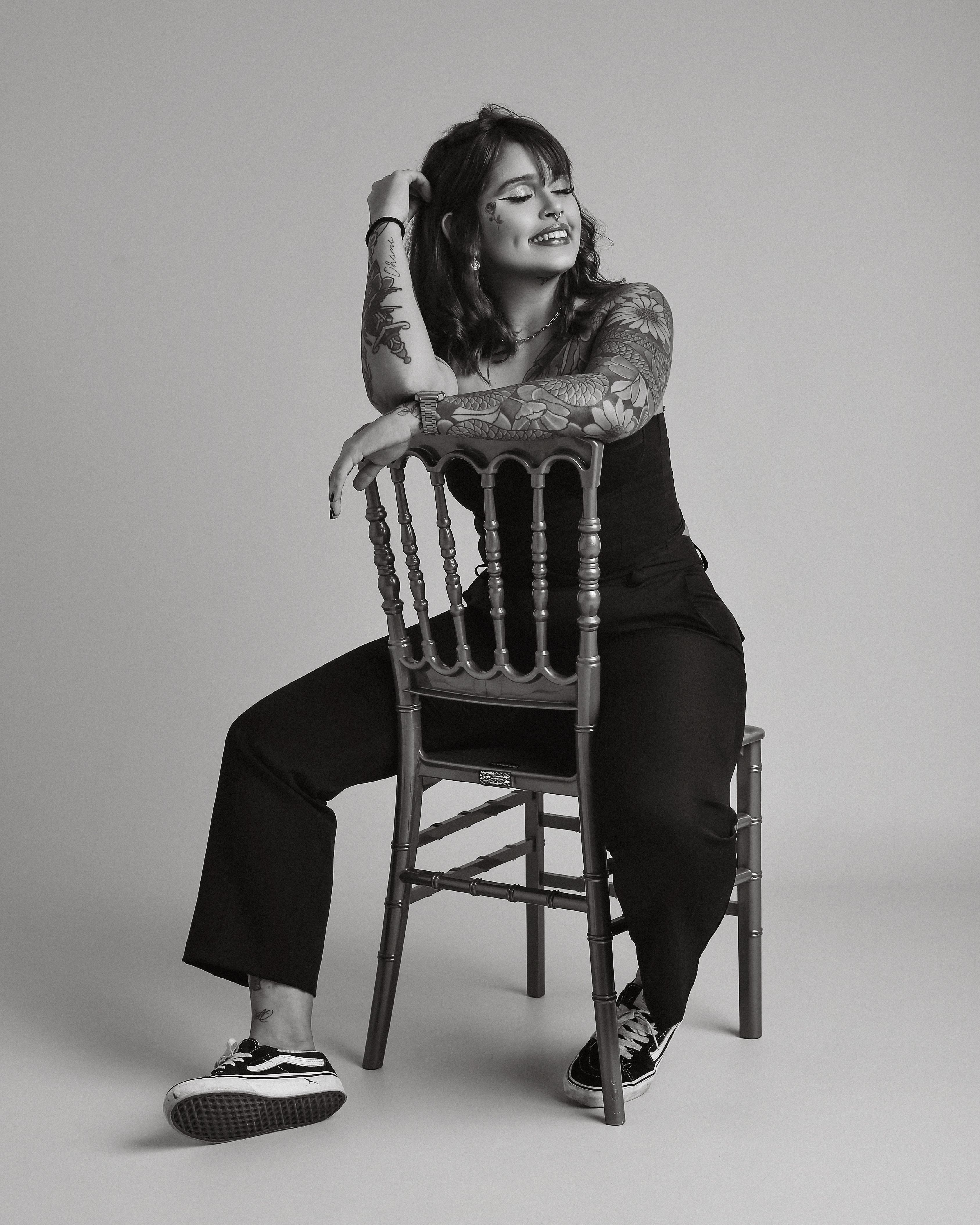 A Tattooed Woman Sitting on a Chair · Free Stock Photo