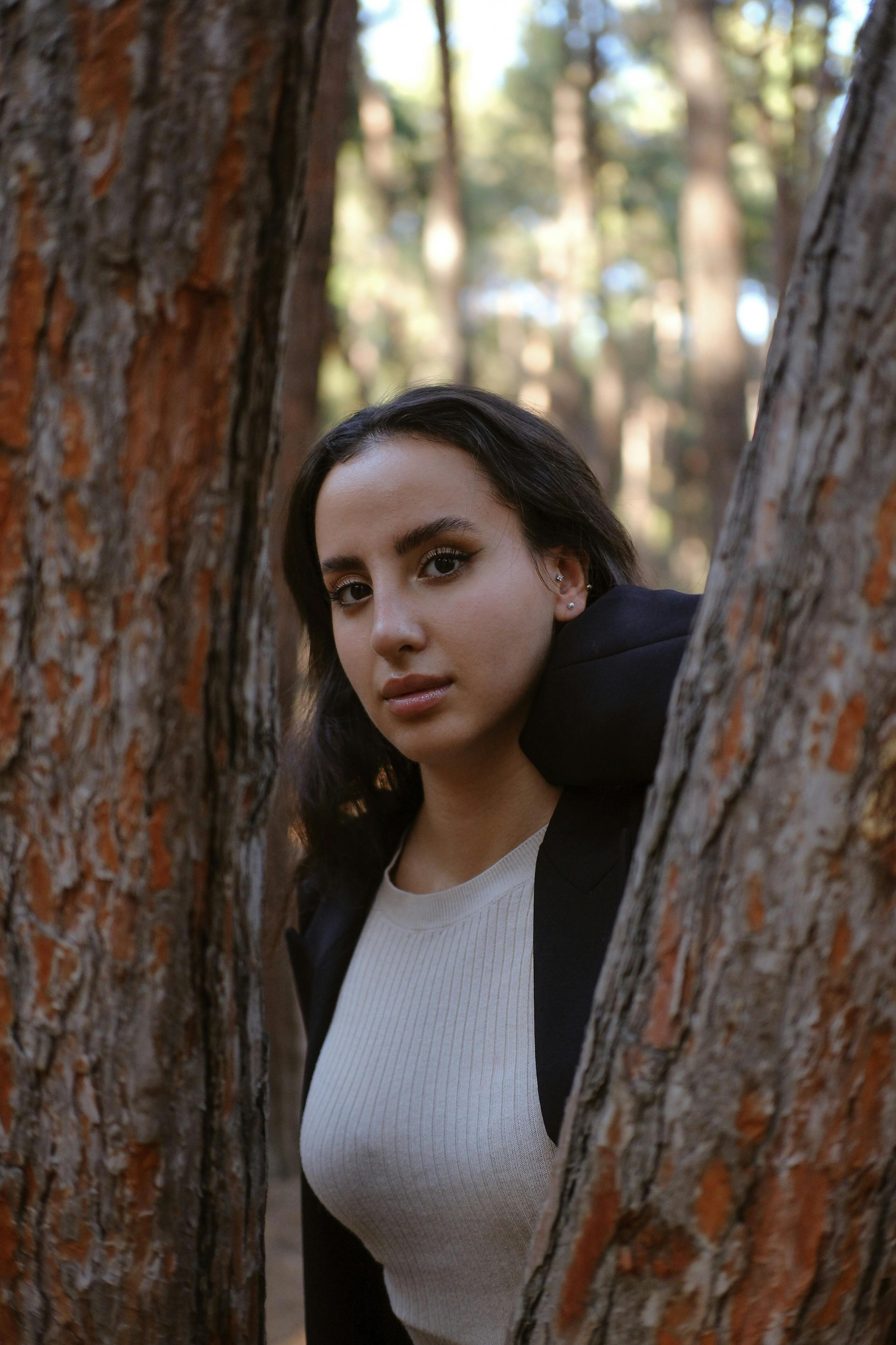 A woman is standing behind a tree · Free Stock Photo