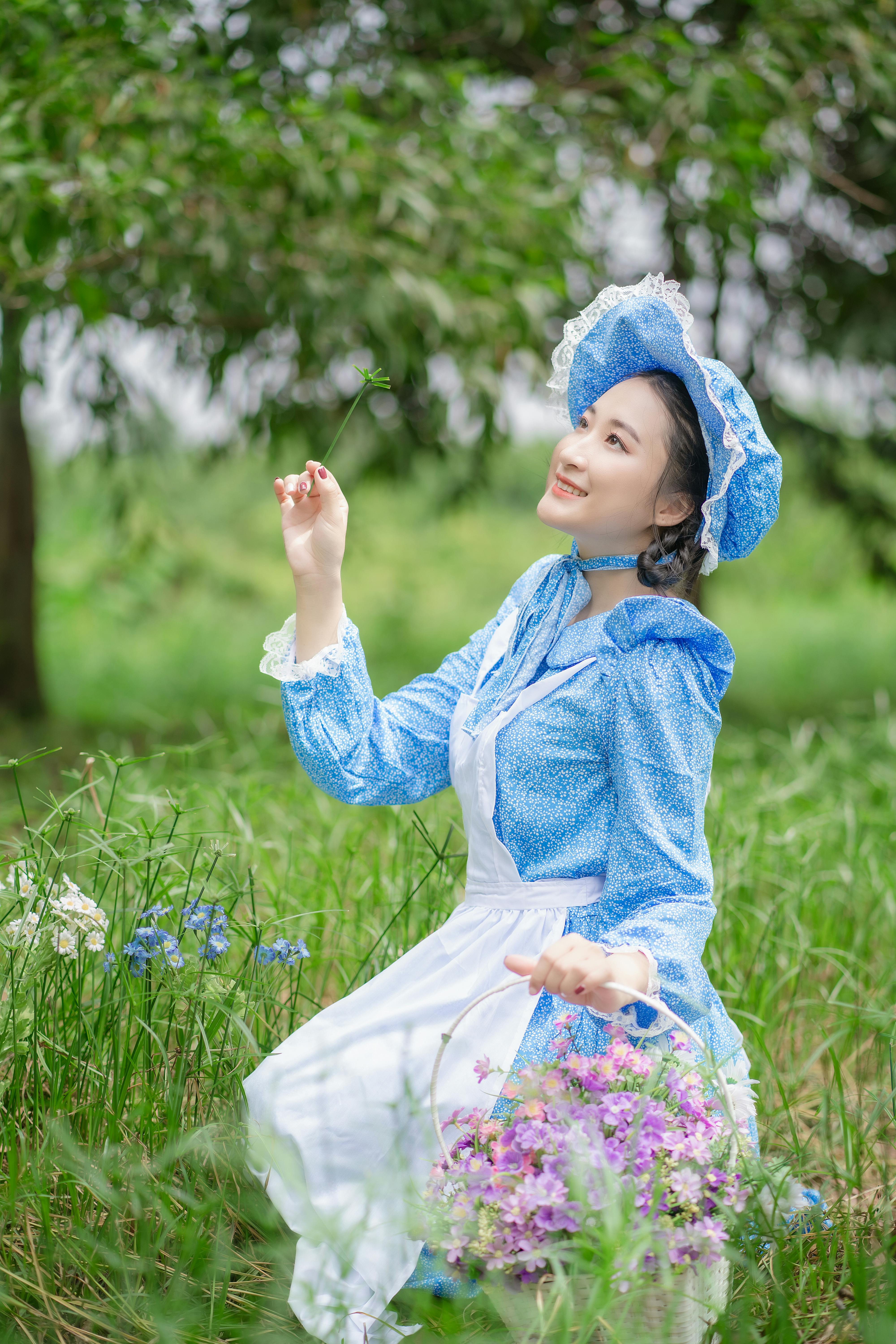 Smiling Woman in Dress and Apron Squatting with Flowers on Meadow ...