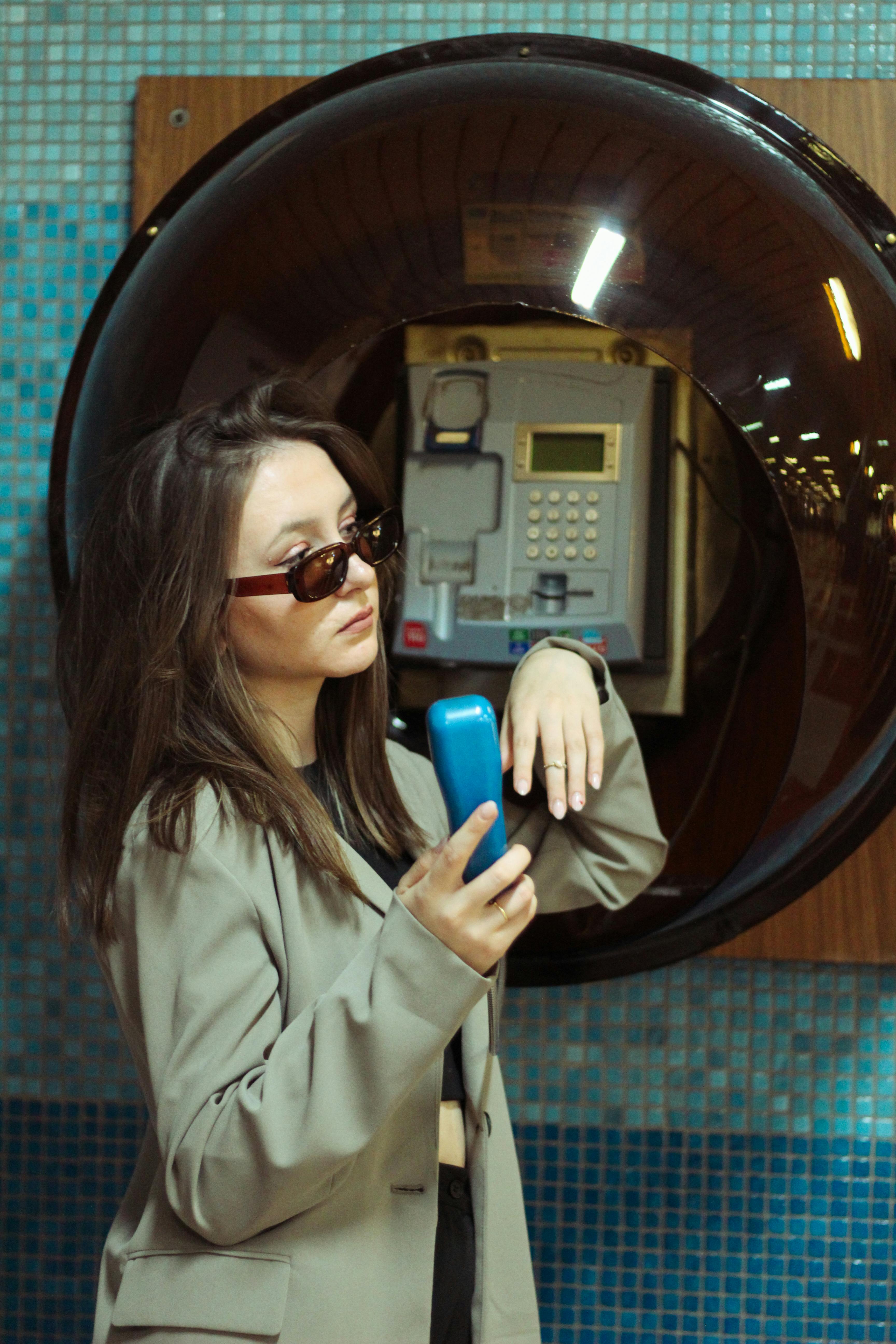 Young Woman Standing next to a Payphone · Free Stock Photo