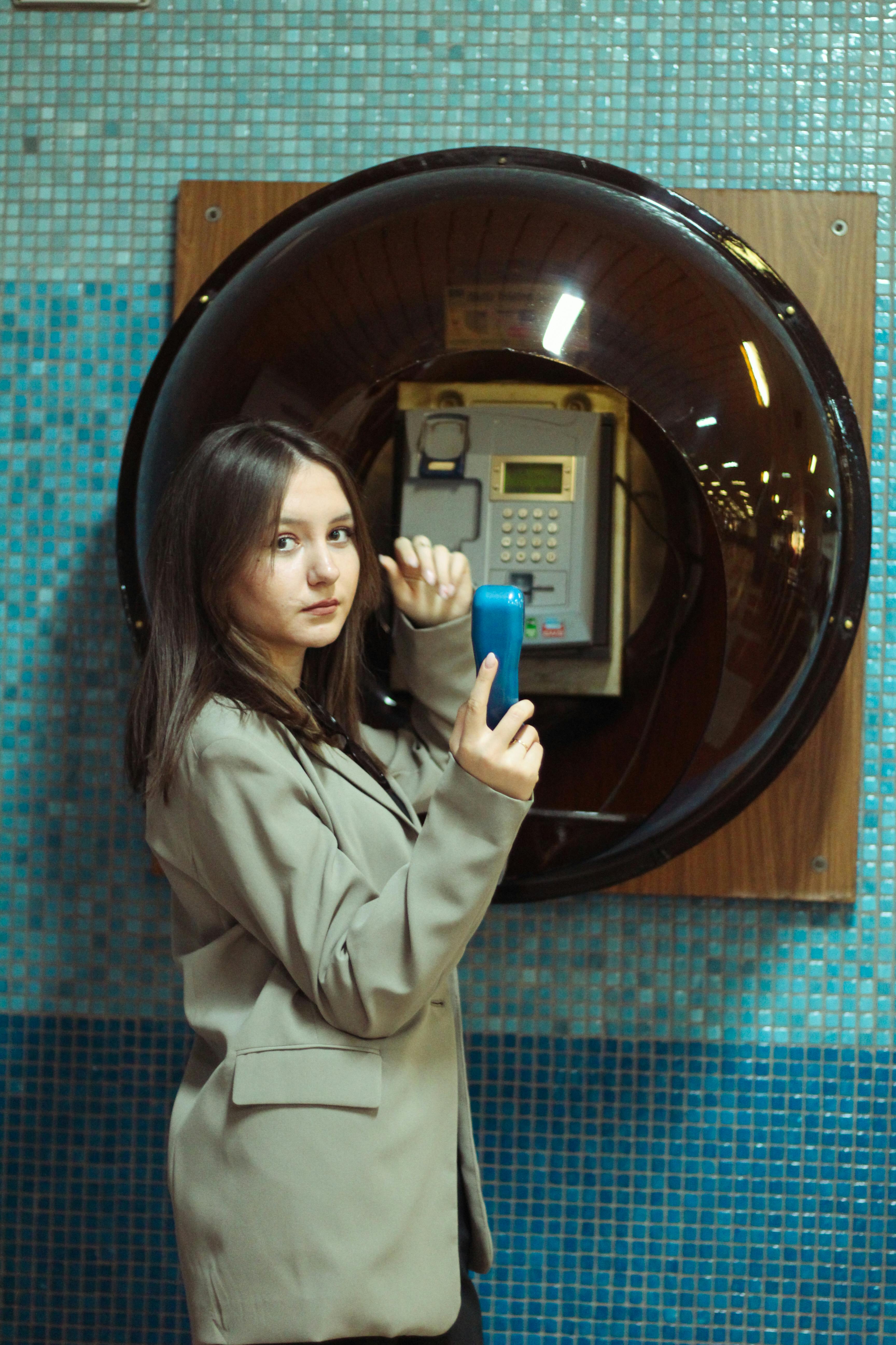Young Woman Standing next to a Payphone · Free Stock Photo