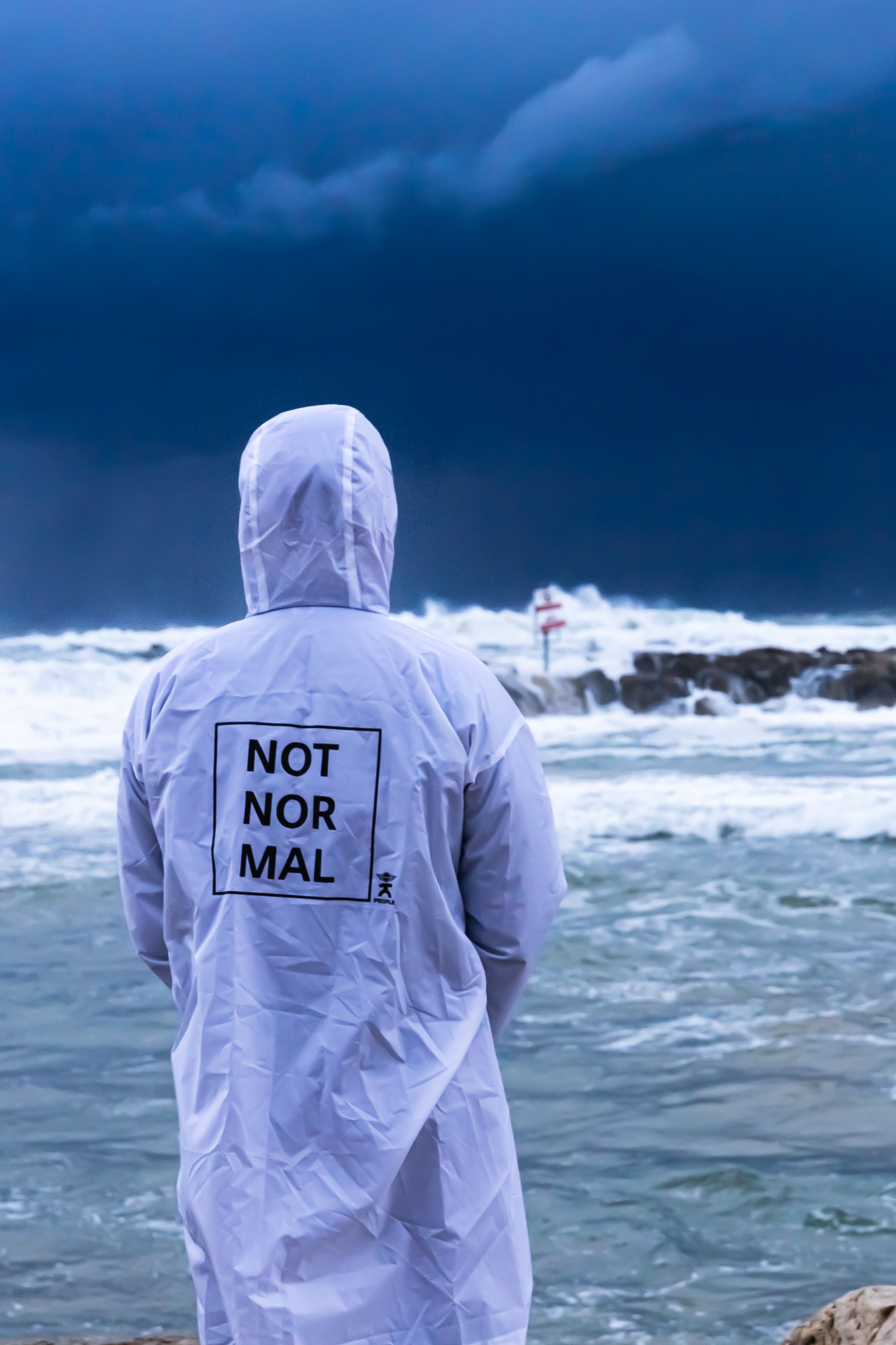 Back View of a Person in a Raincoat Standing on the Shore during a ...