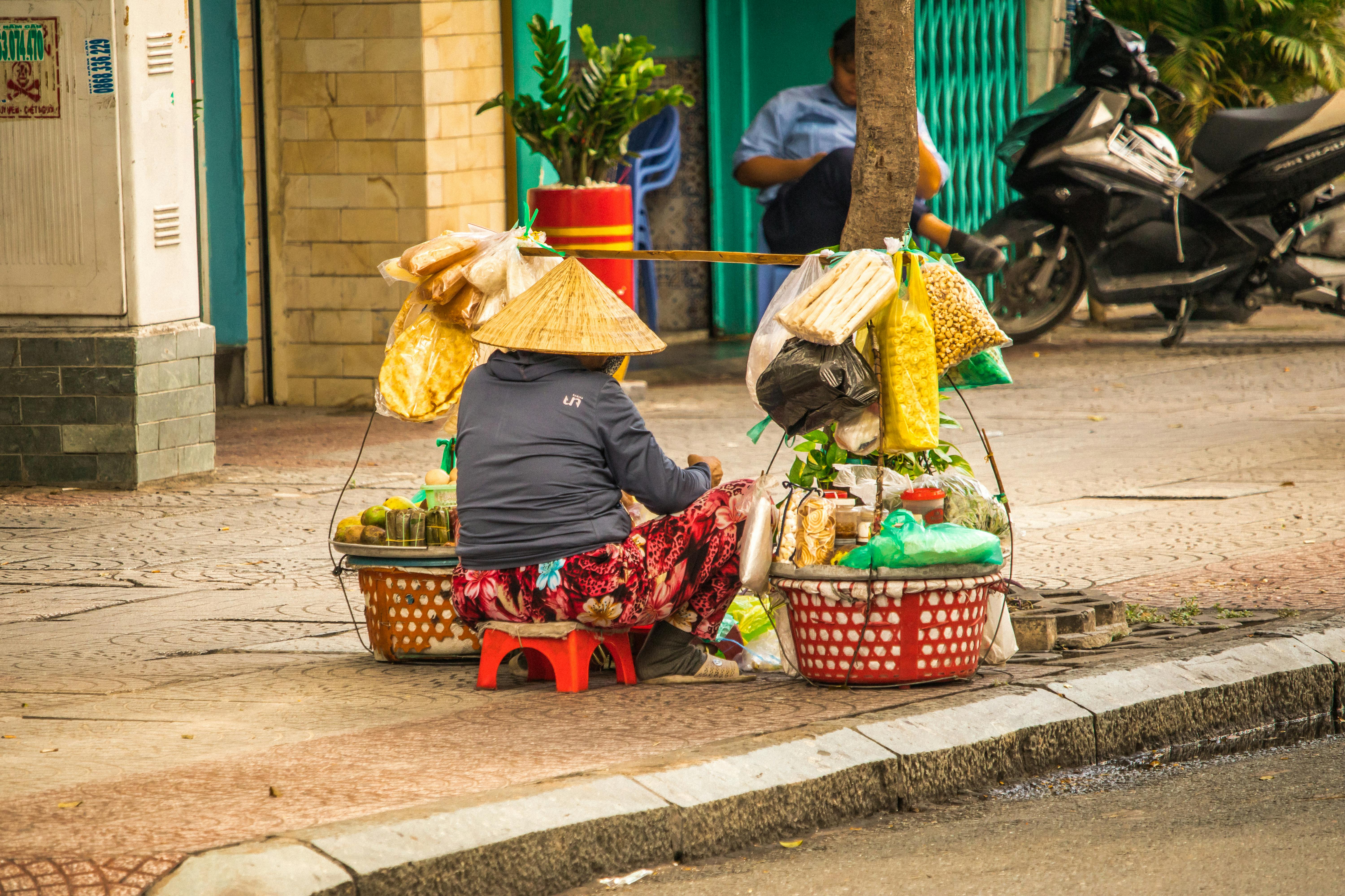 Street Vendor Sitting on Sidewalk · Free Stock Photo