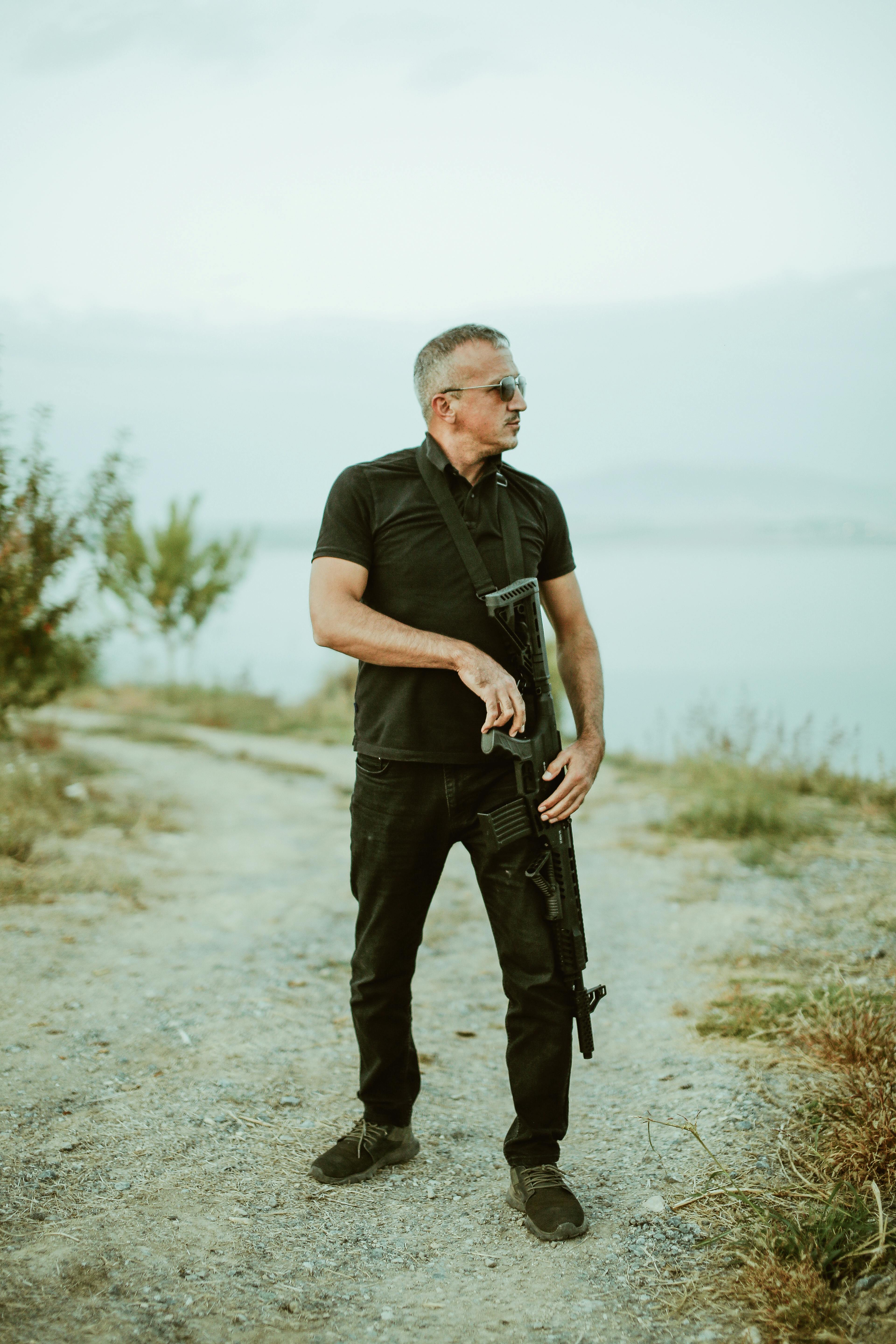Man Standing Outside and Holding a Rifle · Free Stock Photo