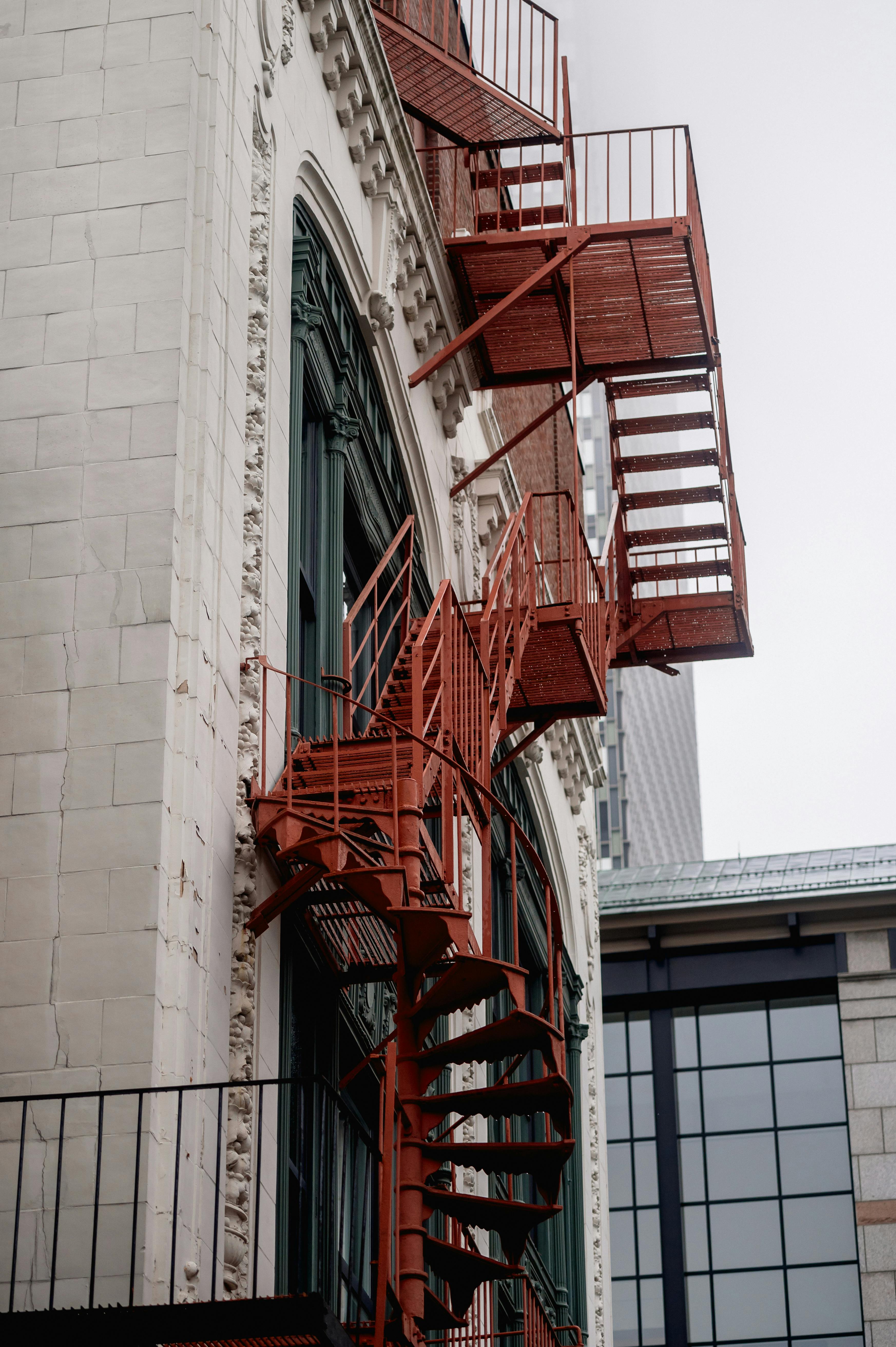 Old Red Metal Fire Escape Ladder on a Building Wall · Free Stock Photo