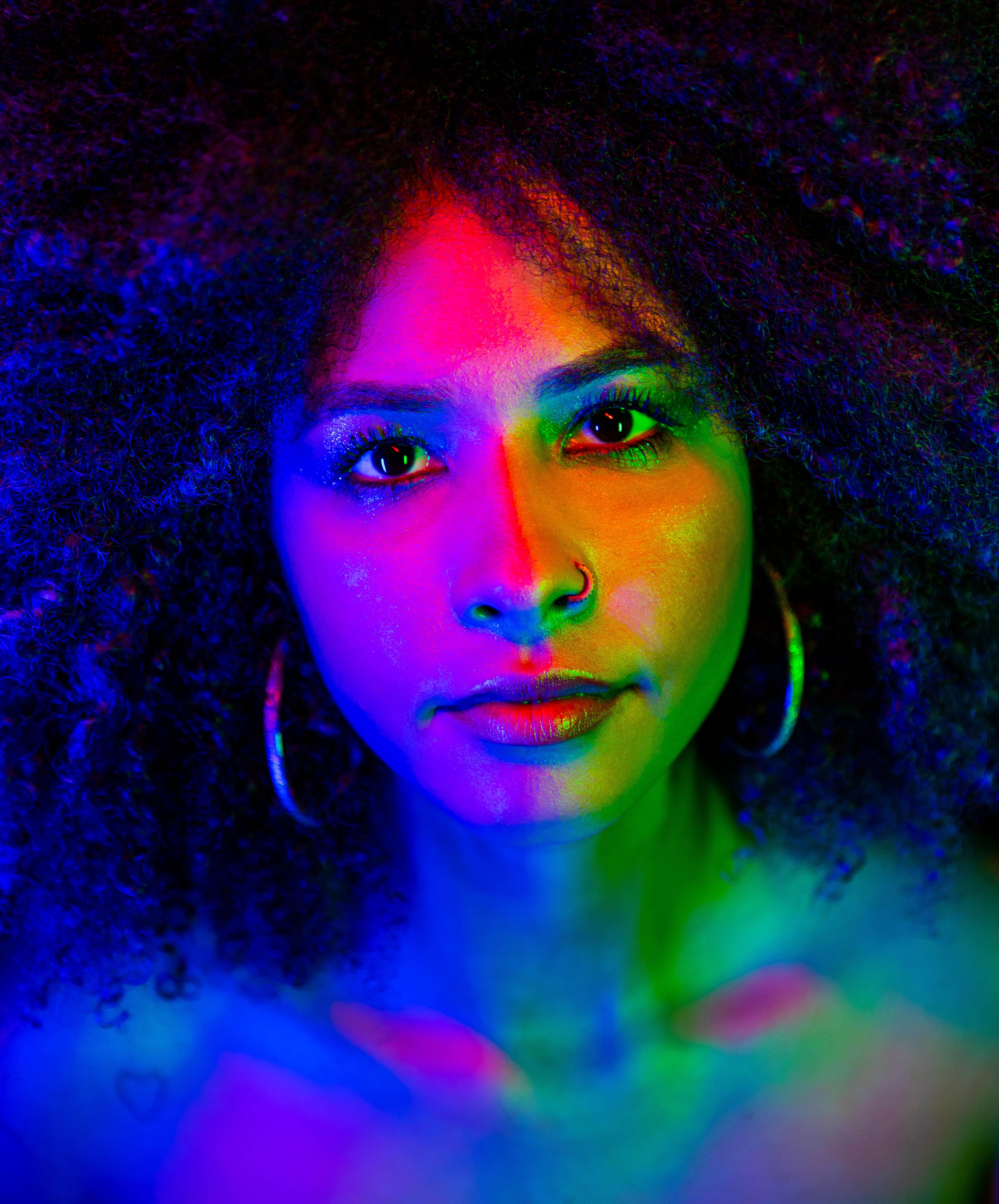 Portrait of a Pretty Brunette Covered in Colorful Lights · Free Stock Photo