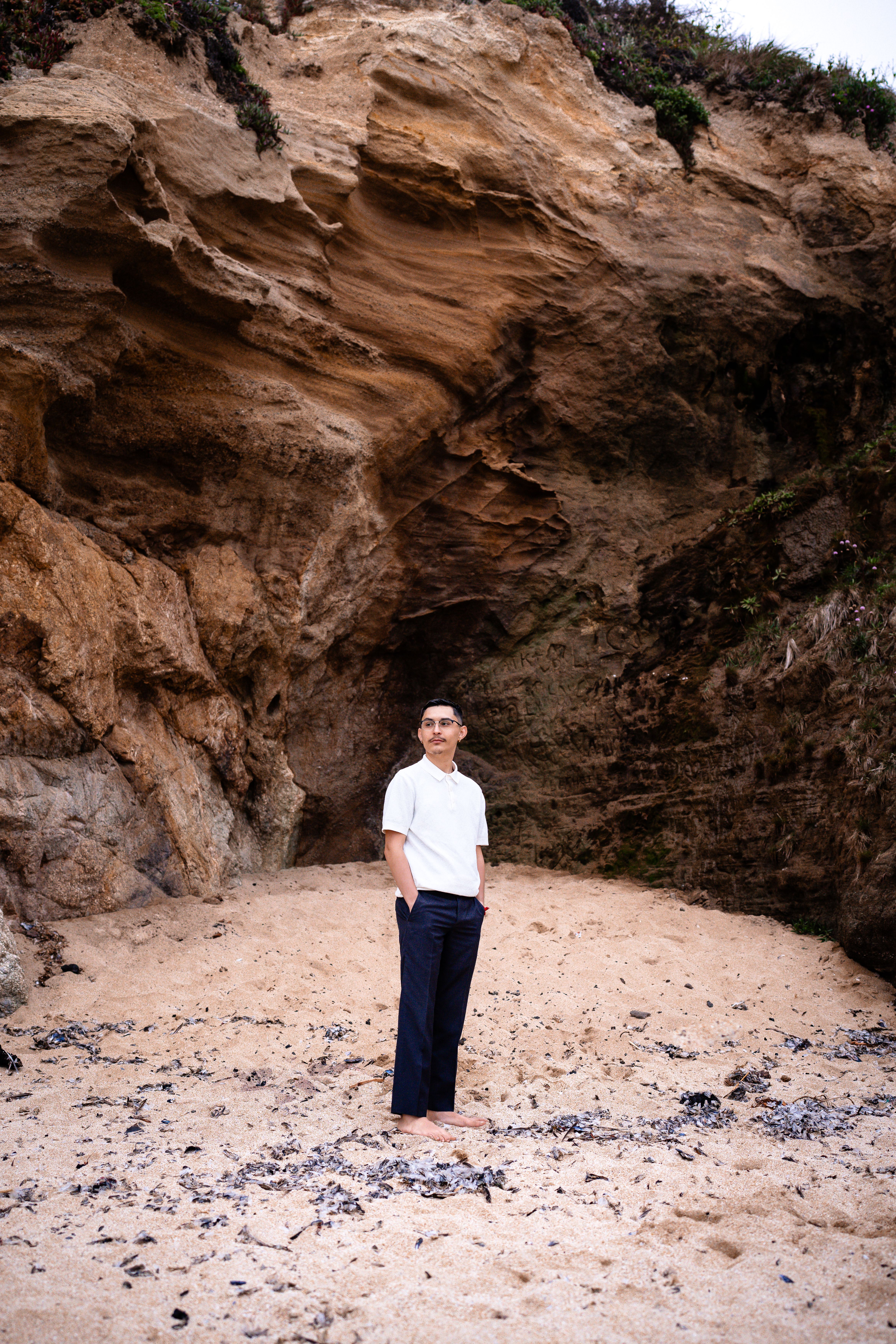 Man Standing on Beach with Rocks behind · Free Stock Photo