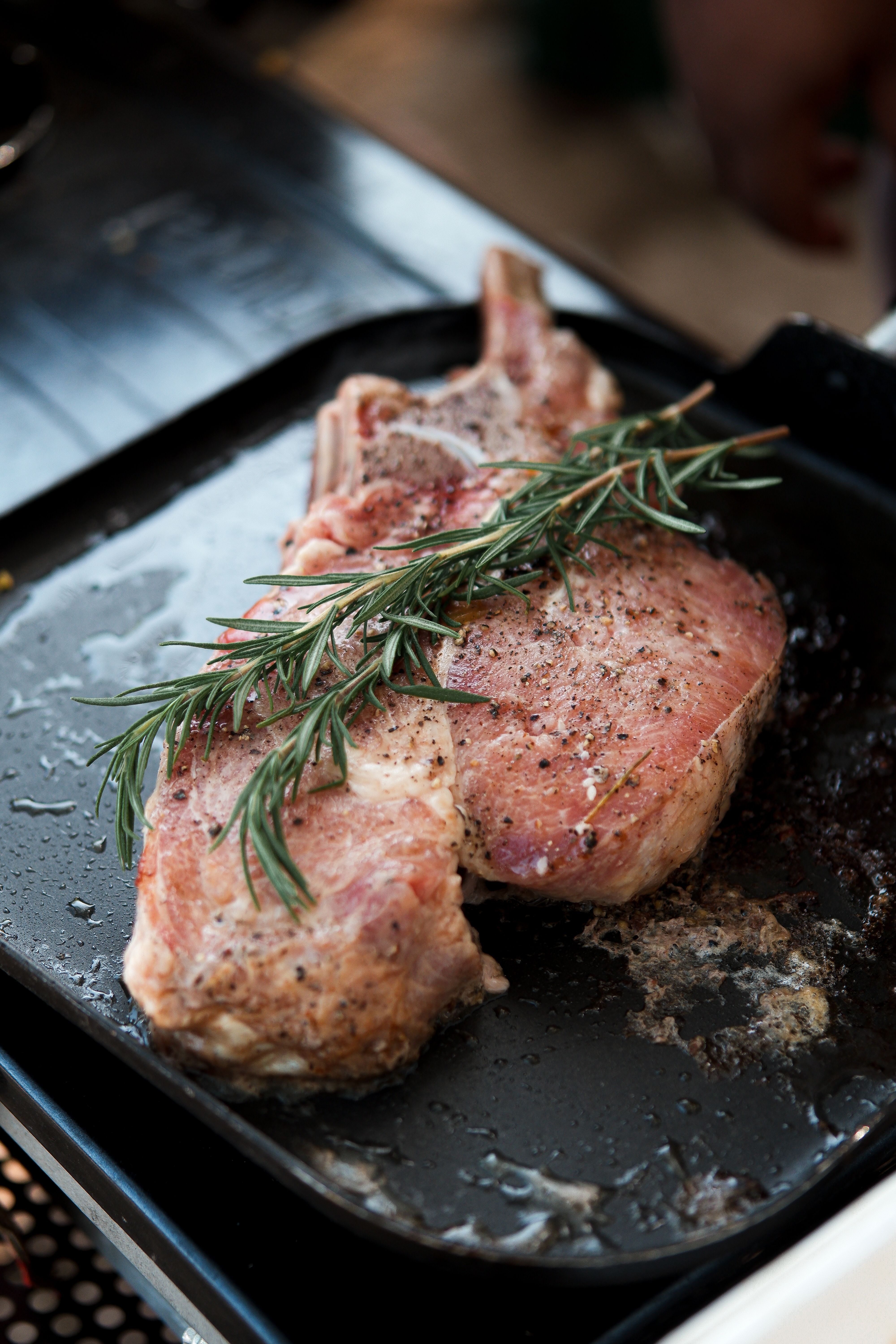 Pork Chops on a Frying Pay with a Sprig of Rosemary · Free Stock Photo