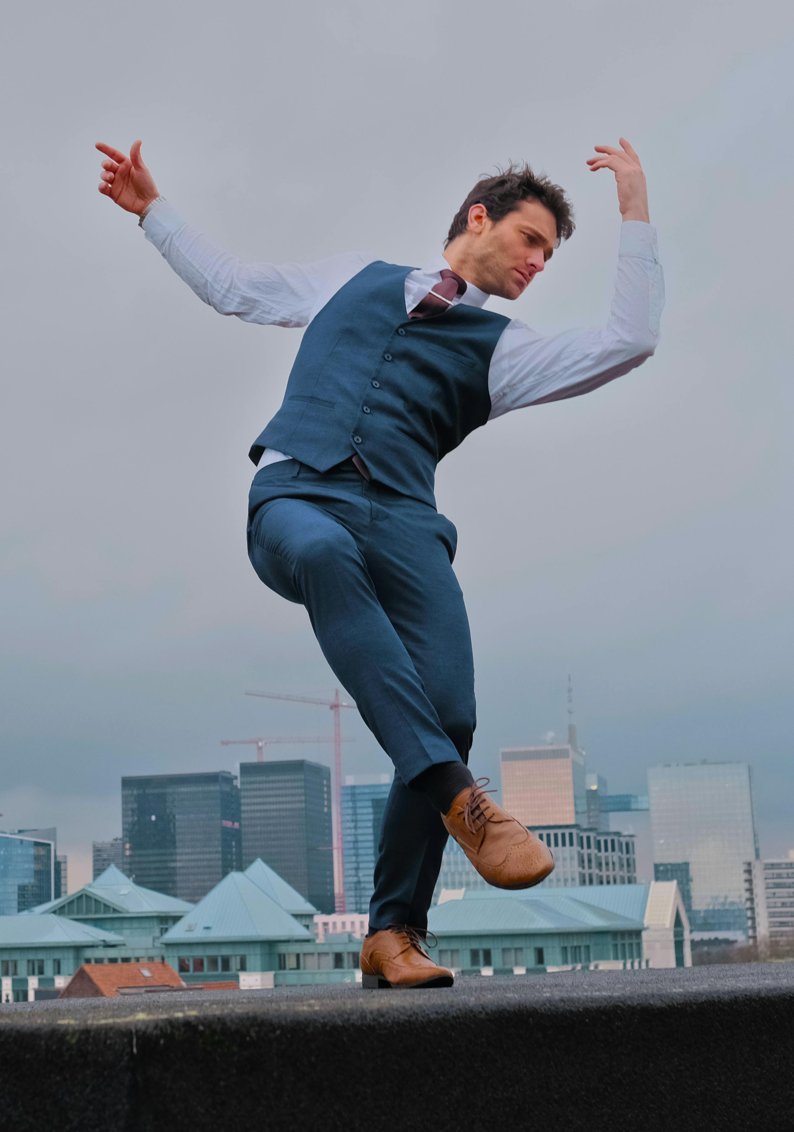 Elegant Man in a Dynamic Pose on a Rooftop in City · Free Stock Photo