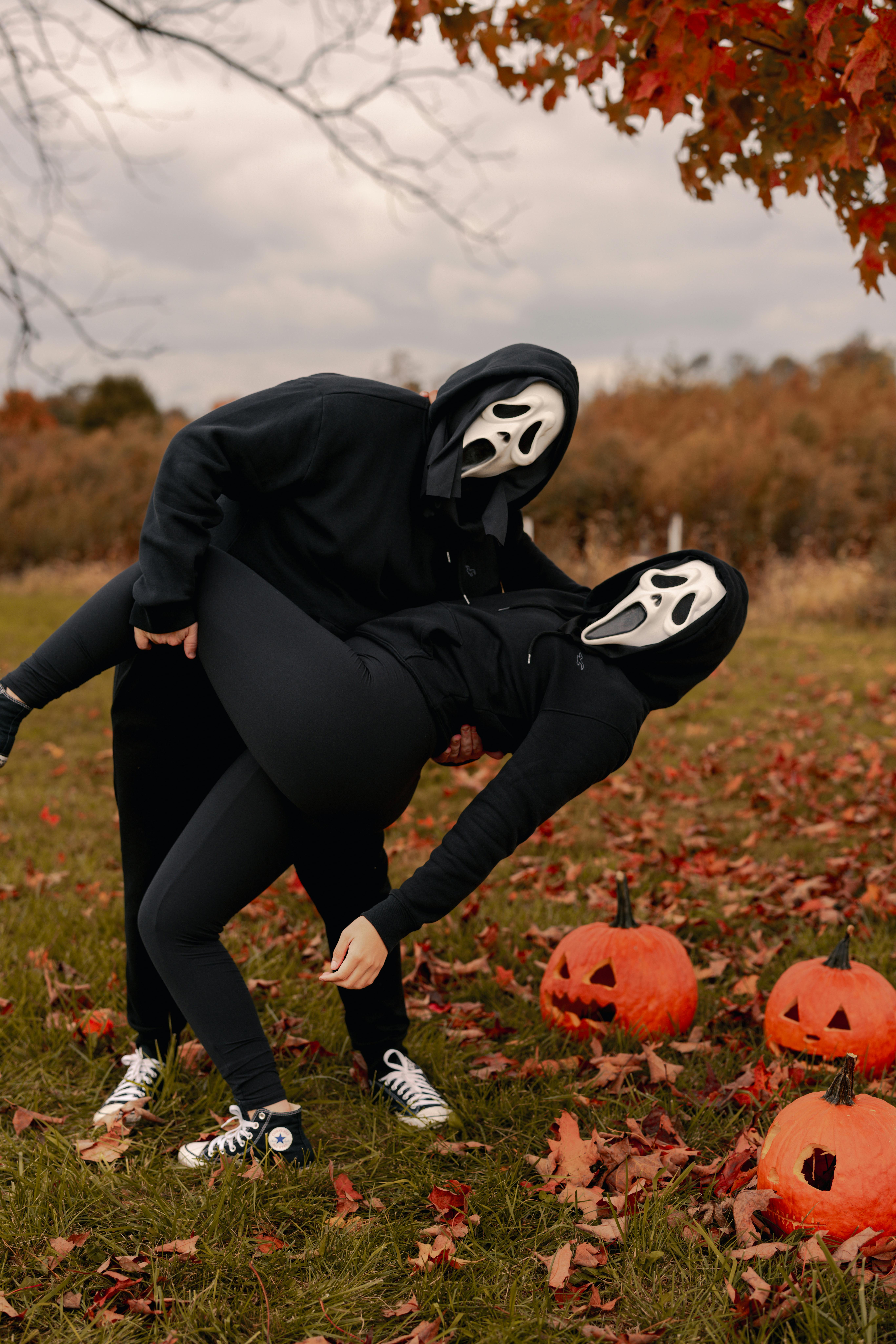 Ghostface Couple Lying on the Grass and Making a Hand Heart Gesture · Free Stock Photo