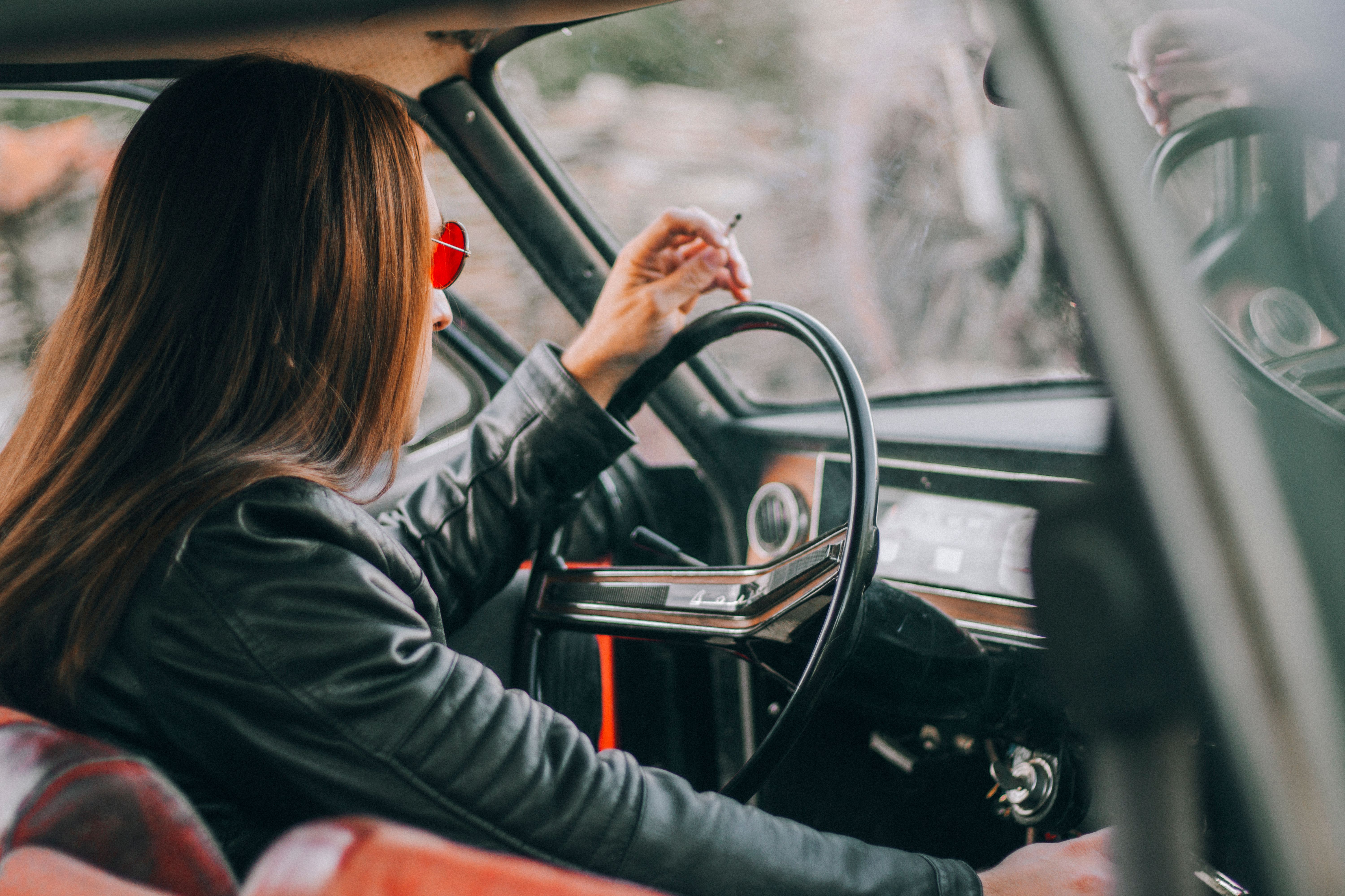 Person with Long Hair Smoking Cigarette in Vintage Car · Free Stock Photo