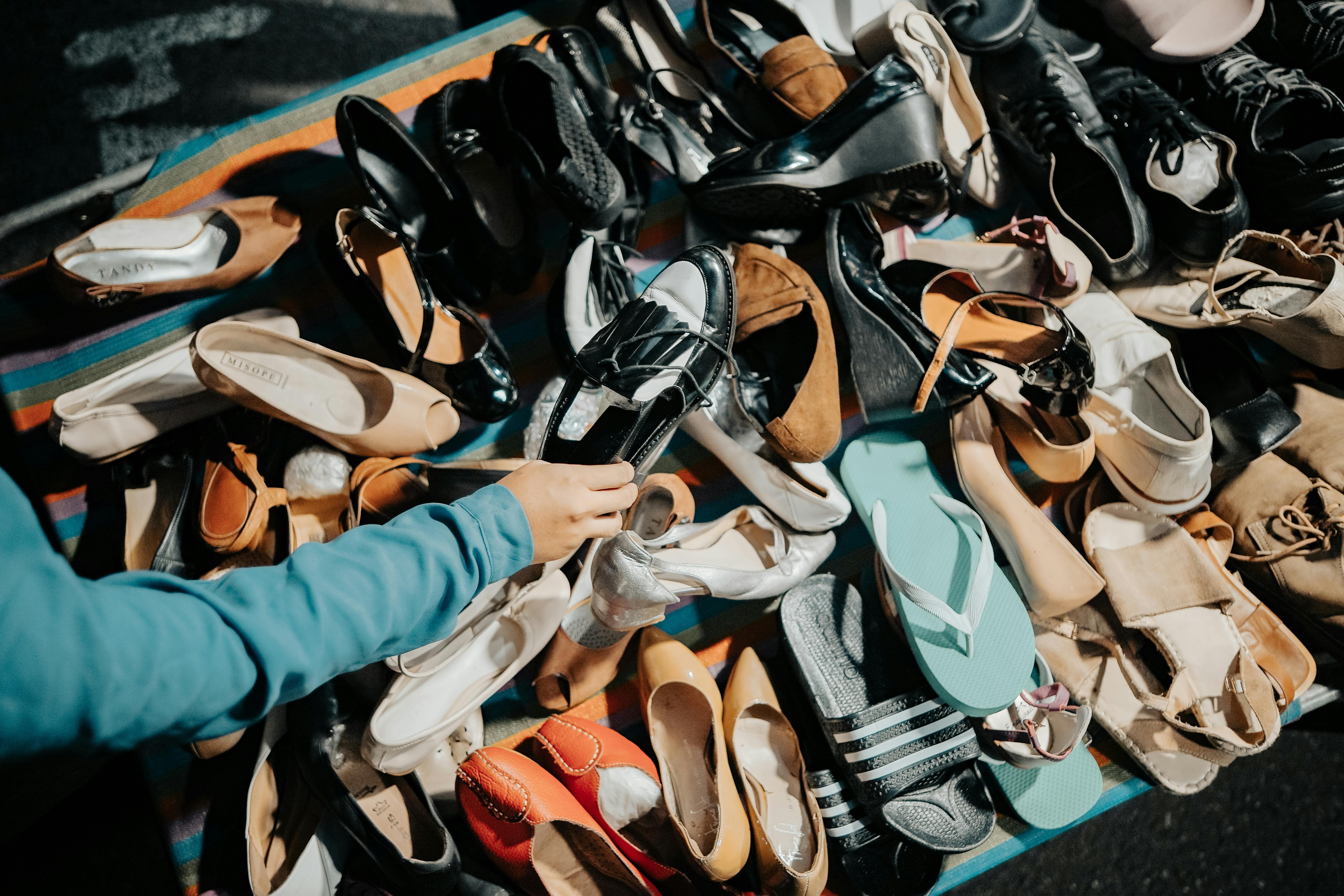 Hand Picking Up Shoes at Market · Free Stock Photo