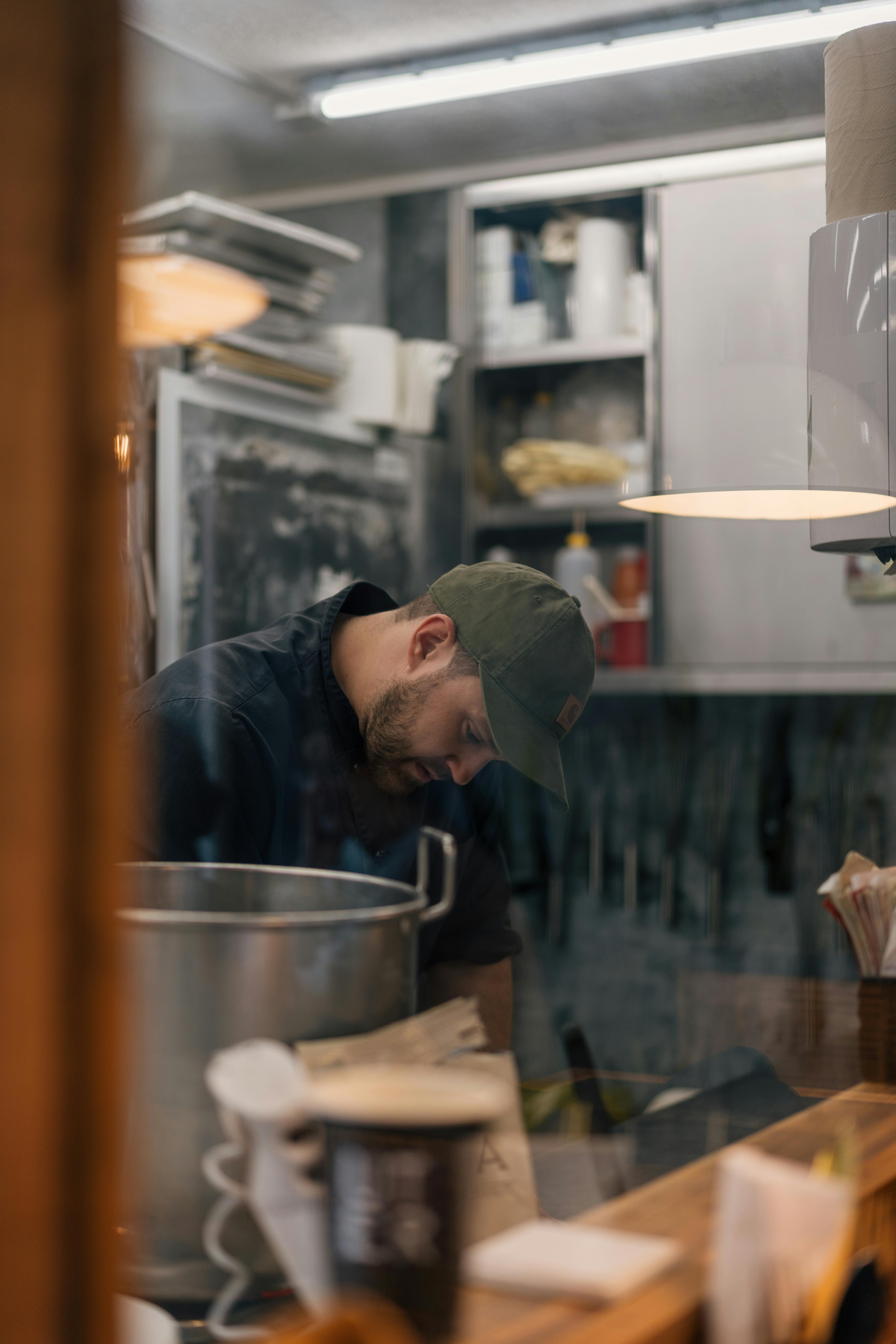 Man in Cap Working in Kitchen behind Window · Free Stock Photo