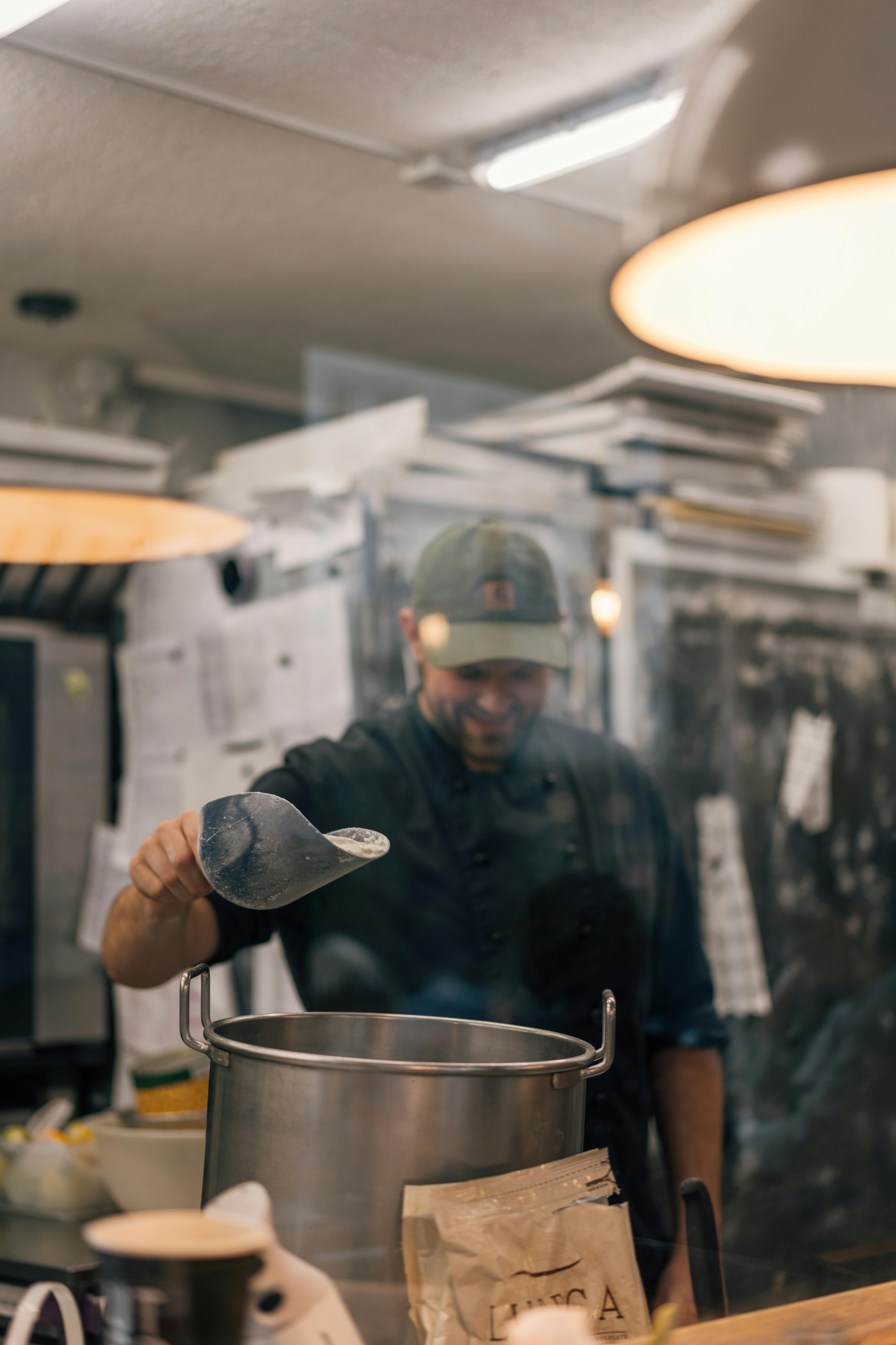 Man in Black Shirt and Baseball Cap Cooking Food at a Restaurant ...