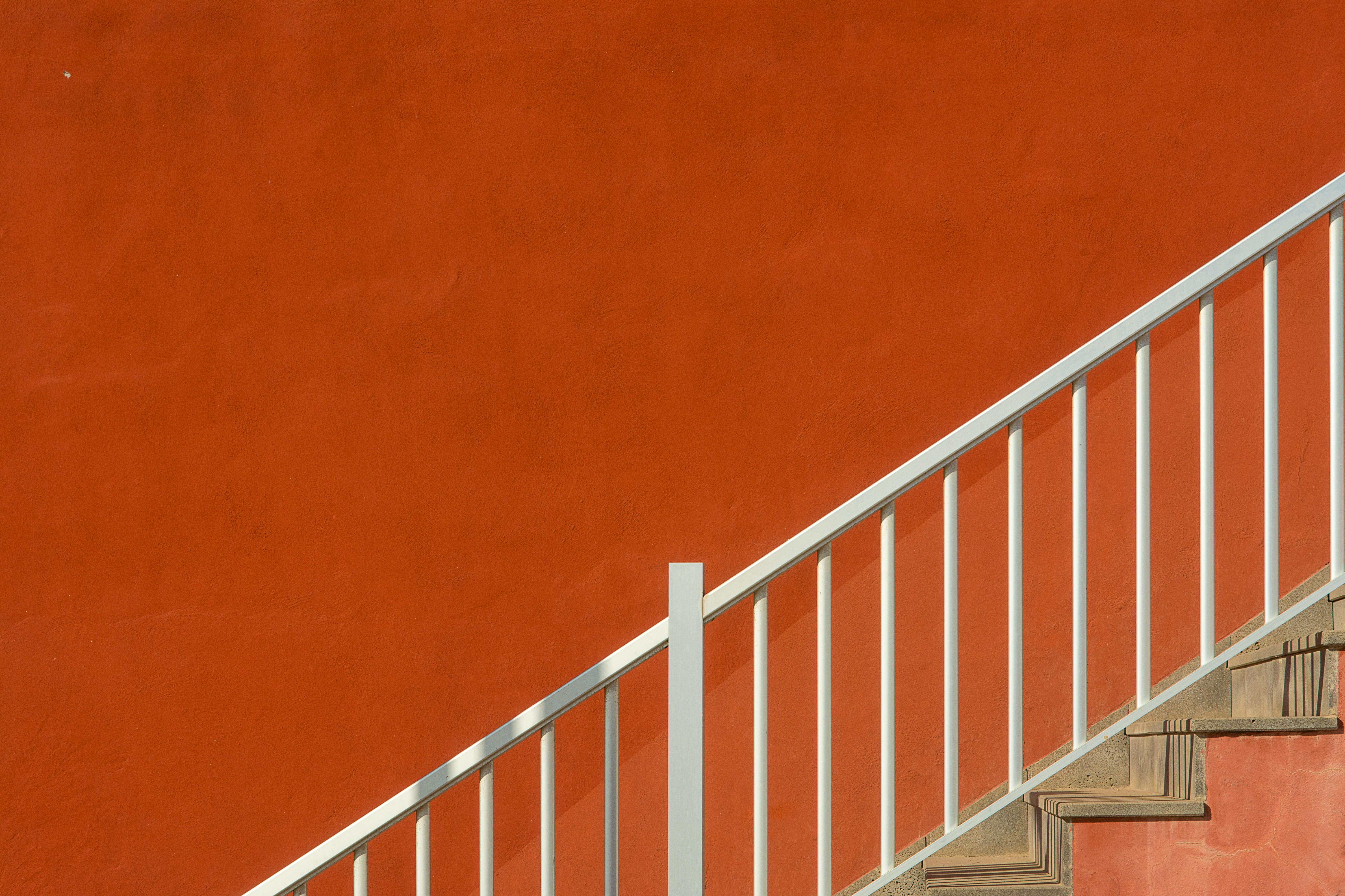 Staircase with White Wooden Railing against Red Wall · Free Stock Photo