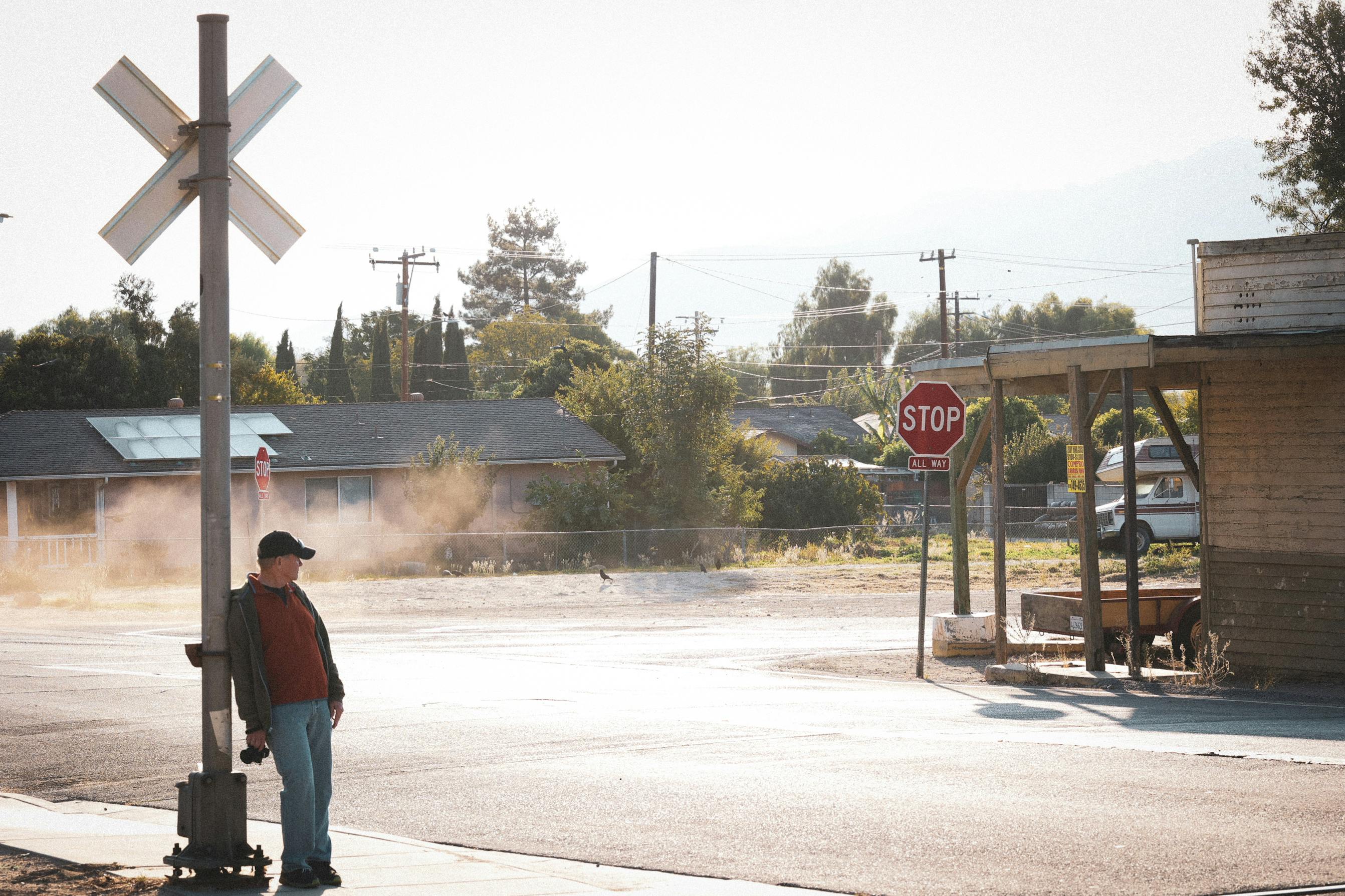 Man Standing by the Road Sign on the Sidewalk · Free Stock Photo