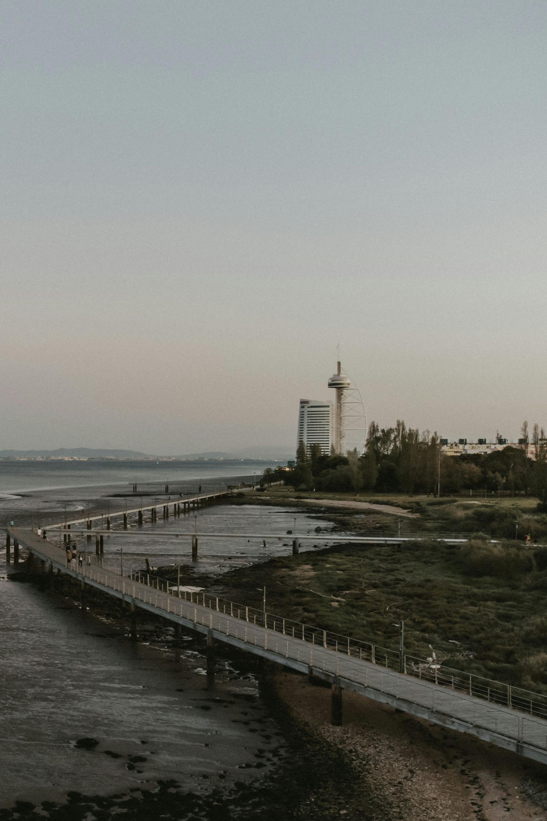 A long pier with a lighthouse in the distance · Free Stock Photo