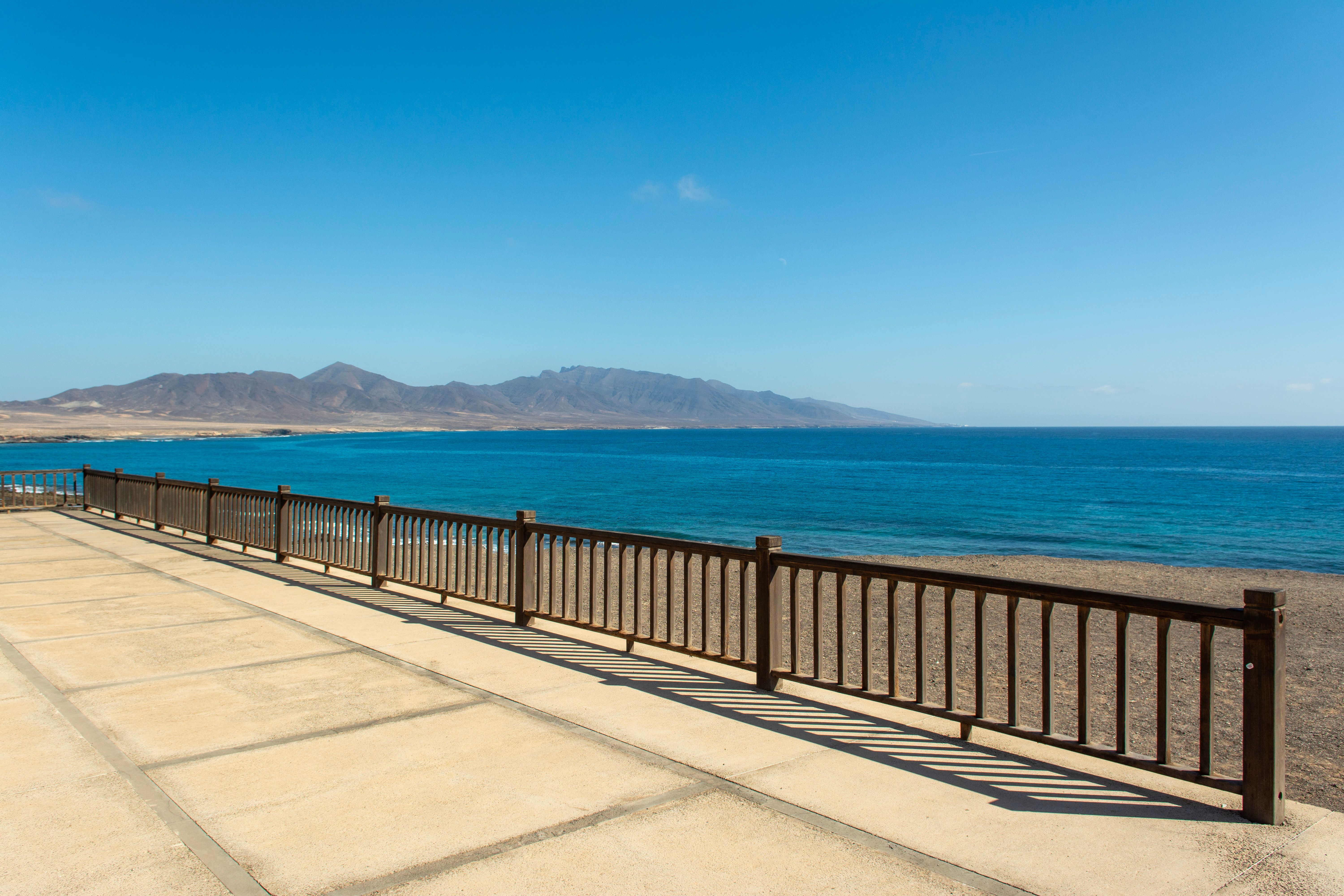 Sunlit Pavement with Railing by Beach on Sea Shore · Free Stock Photo