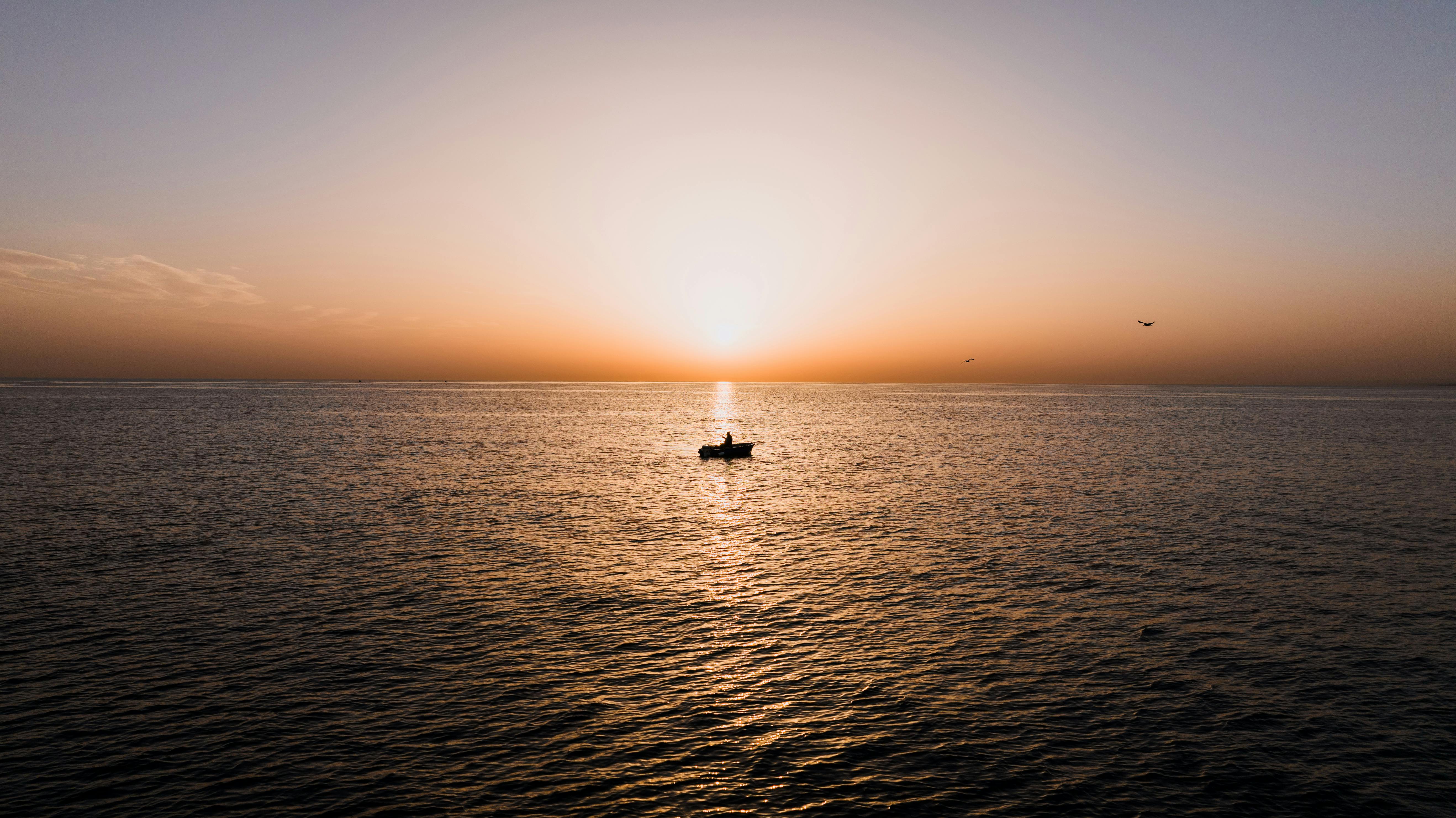 Person on Boat Alone on Ocean at Dusk · Free Stock Photo