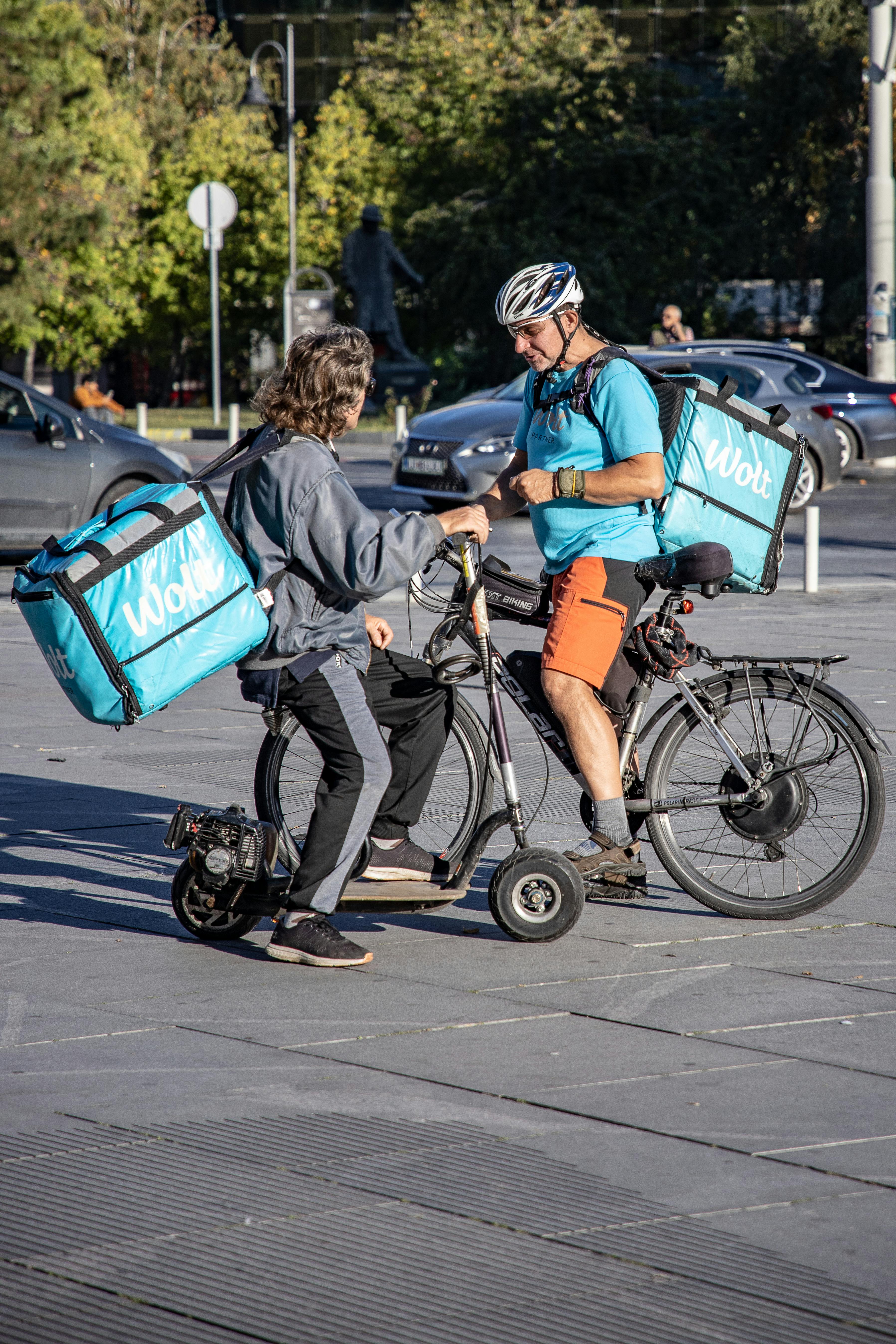Wolt Delivery Drivers on Electric Scooter and Bicycle · Free Stock Photo