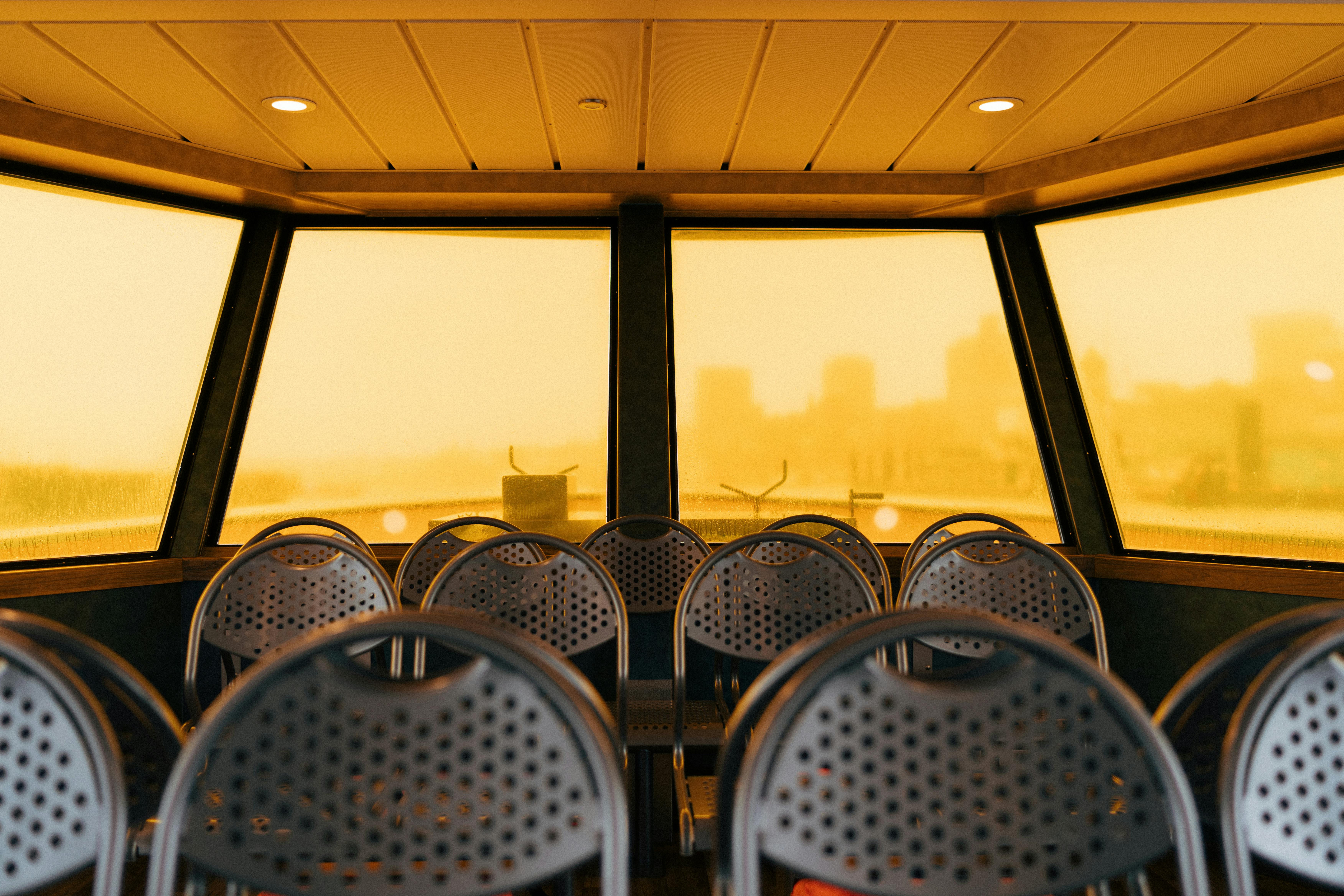 Yellow and Wet Ferry Windows Over Metal Chairs · Free Stock Photo