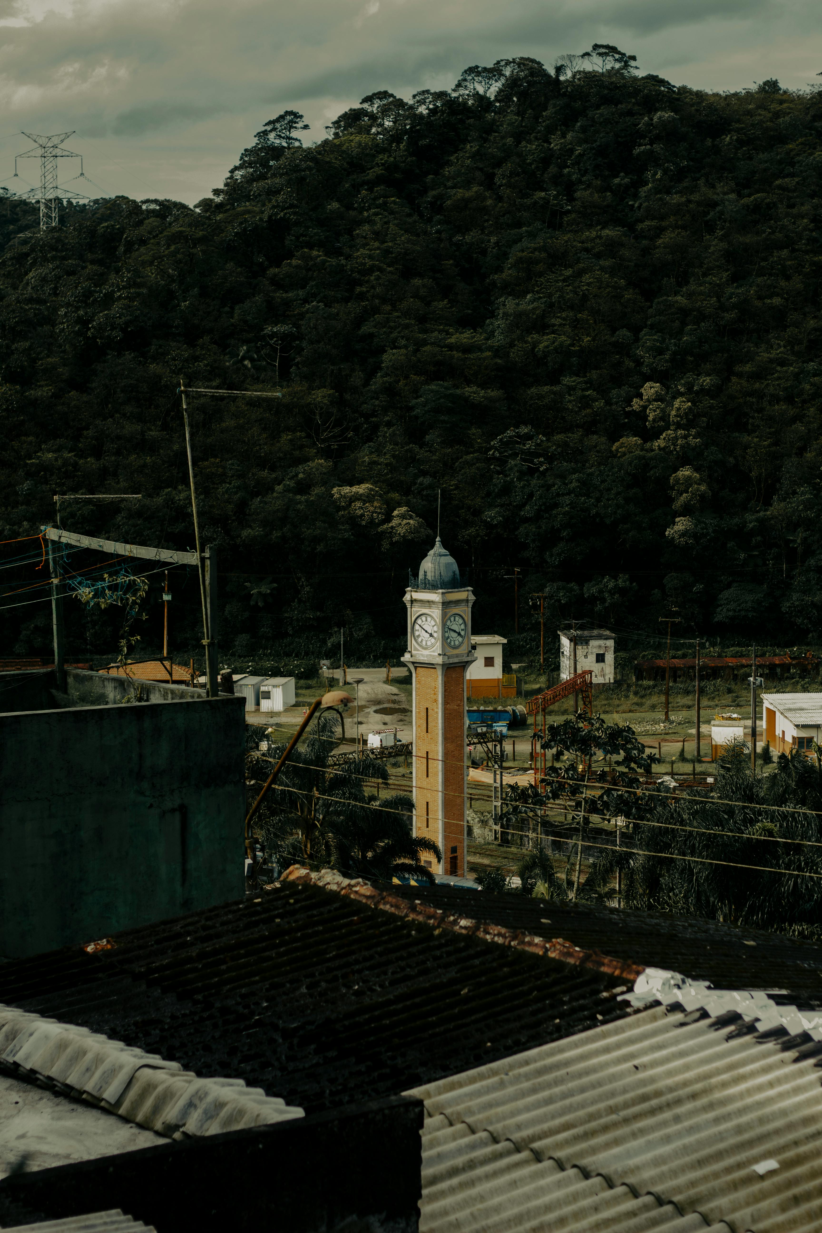 Clock Tower behind Building Roof in Town · Free Stock Photo