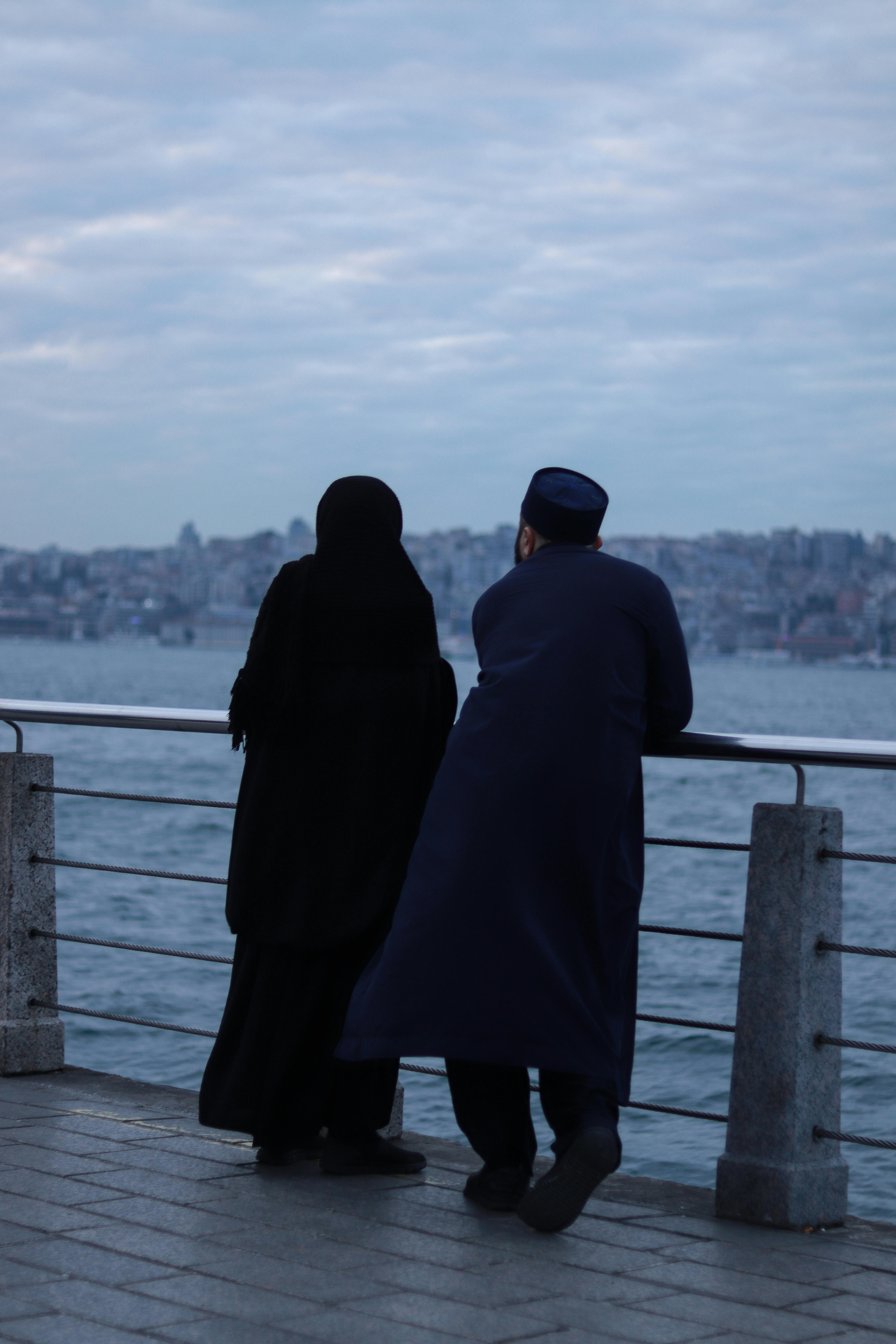 Modestly Dressed Couple Standing on Bridge over Lake · Free Stock Photo