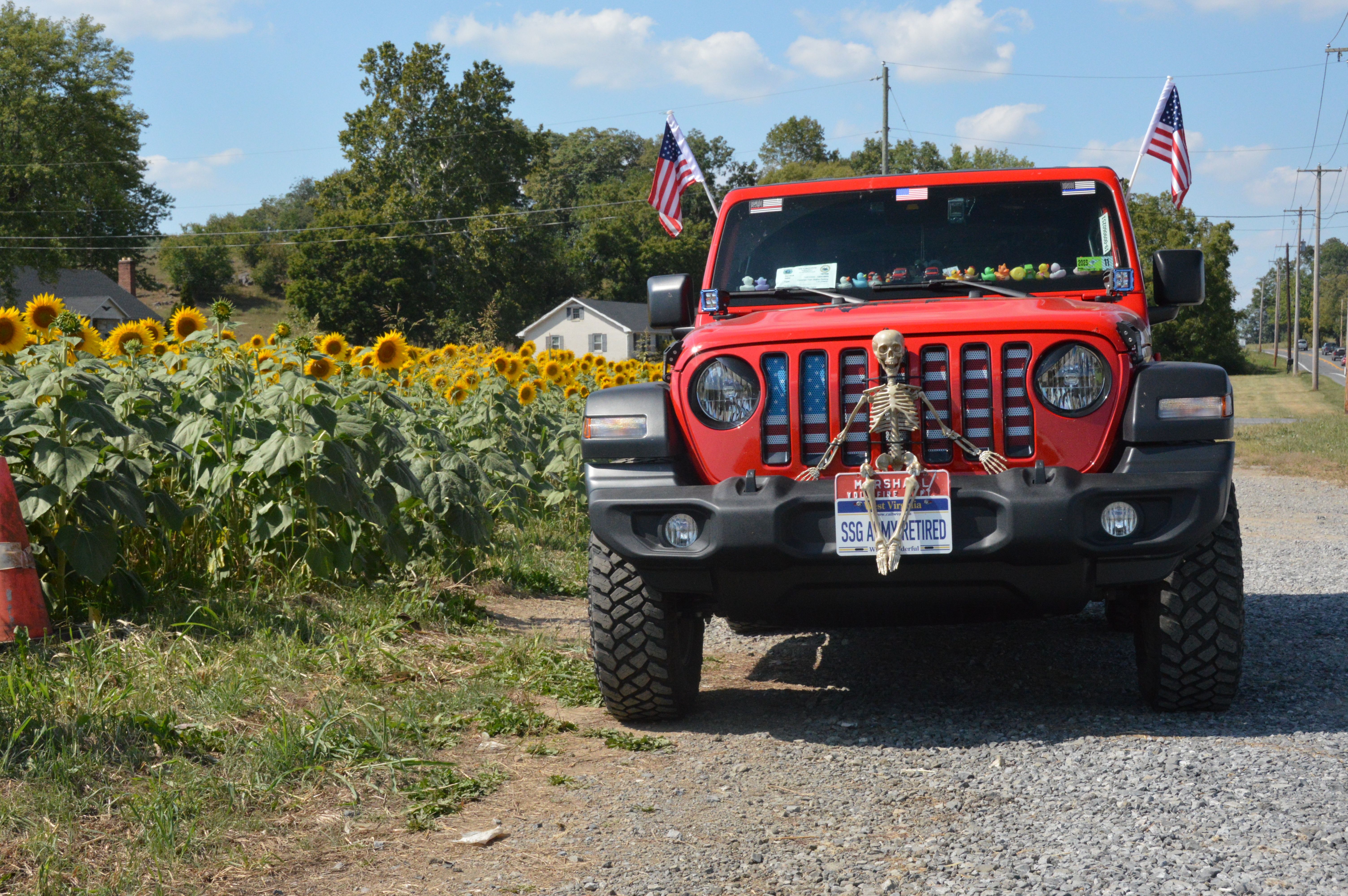 Red Jeep with Skeleton by Field of Sunflowers · Free Stock Photo