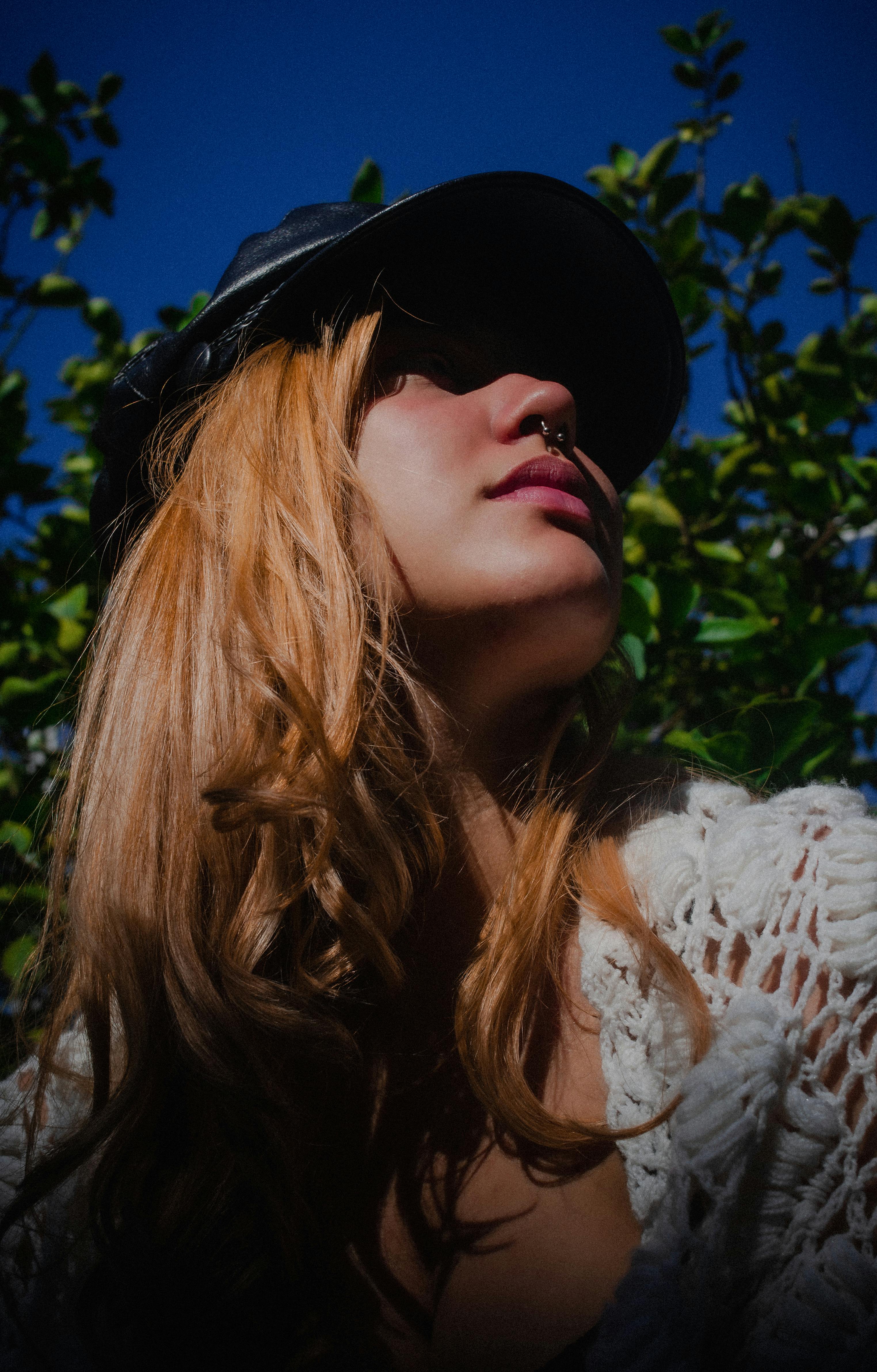 Pretty Blonde Woman in Black Cap Looking Up · Free Stock Photo