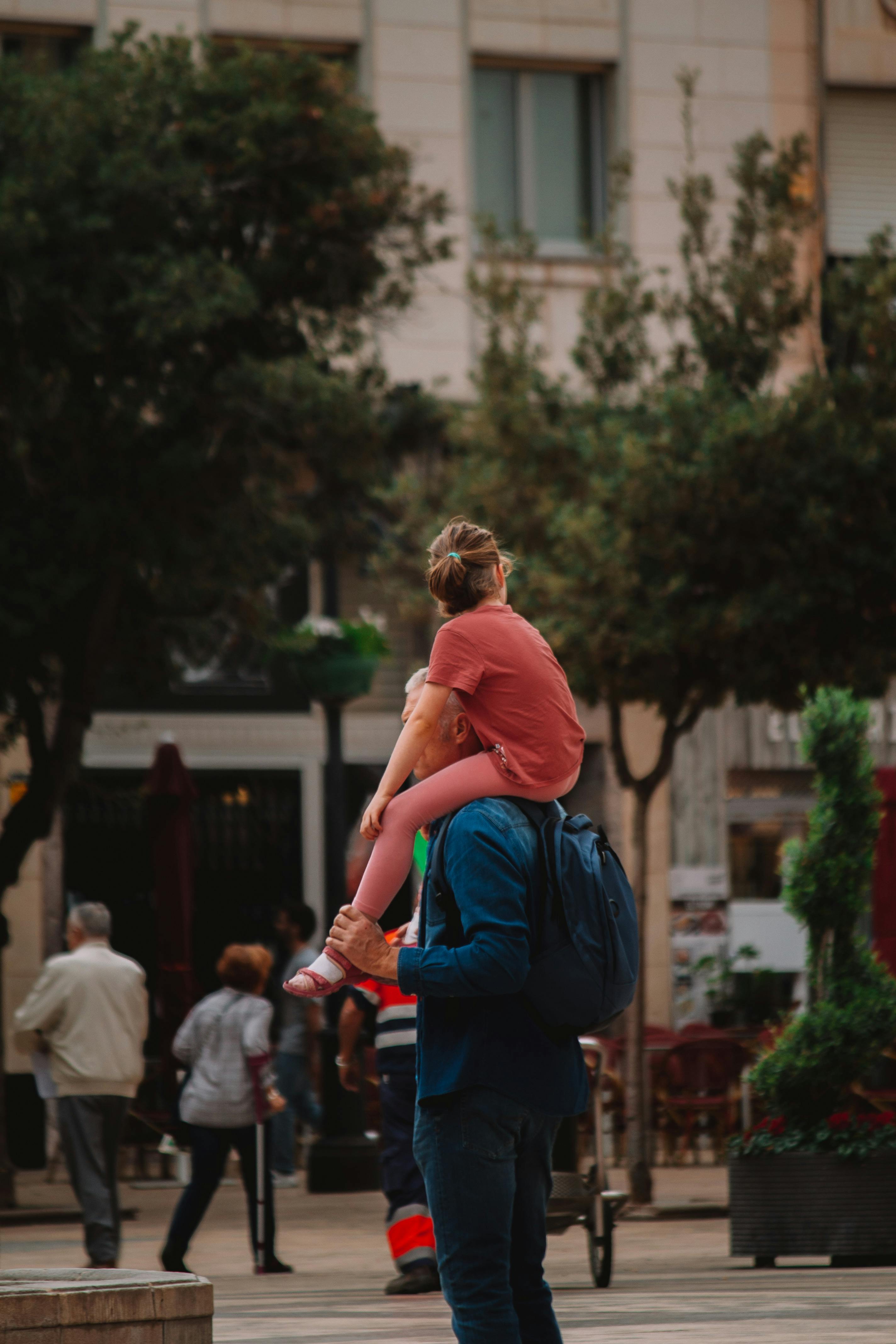 A Man Carrying a Child on His Shoulders · Free Stock Photo