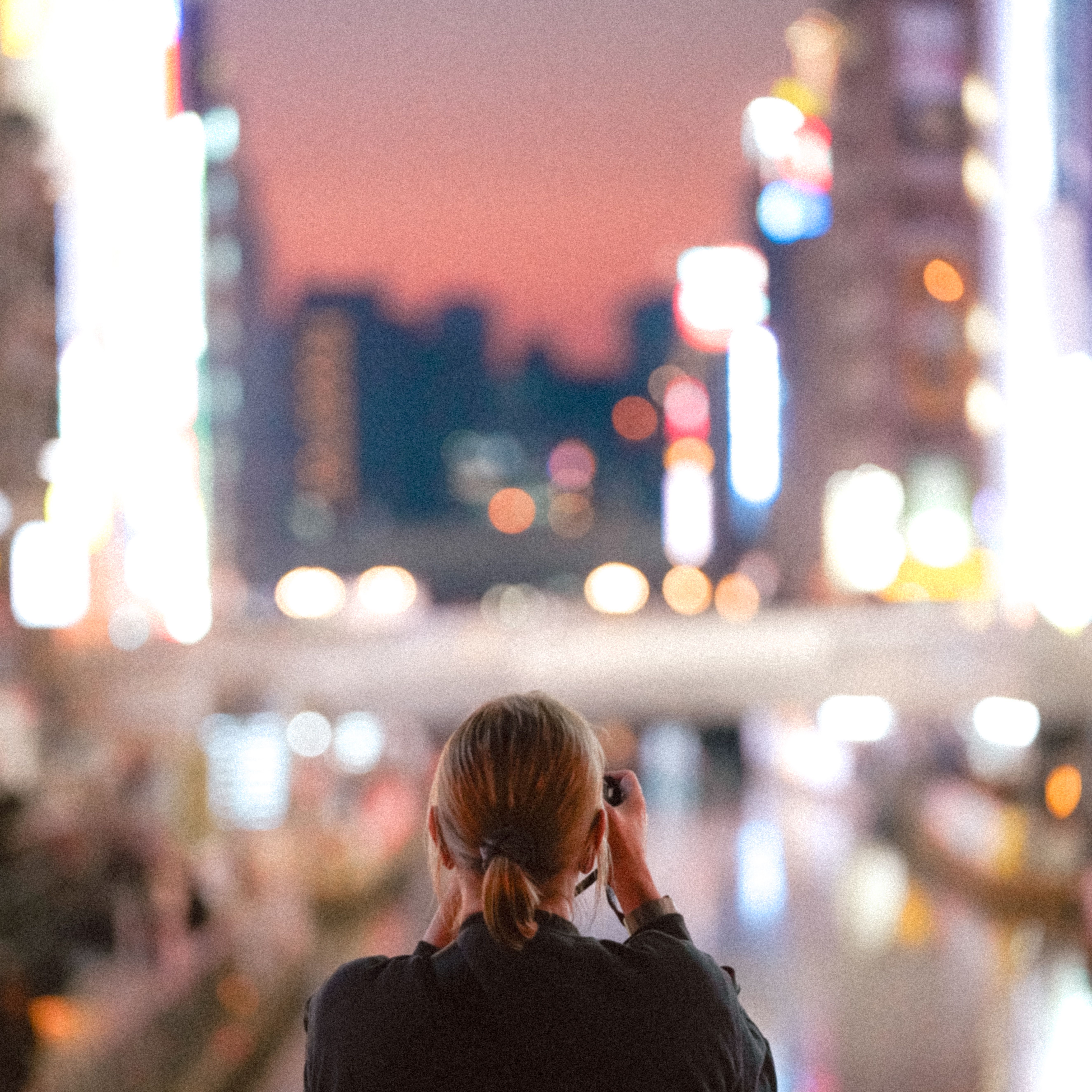 Back View of a Woman Standing on the Background of Blurry City Lights ...