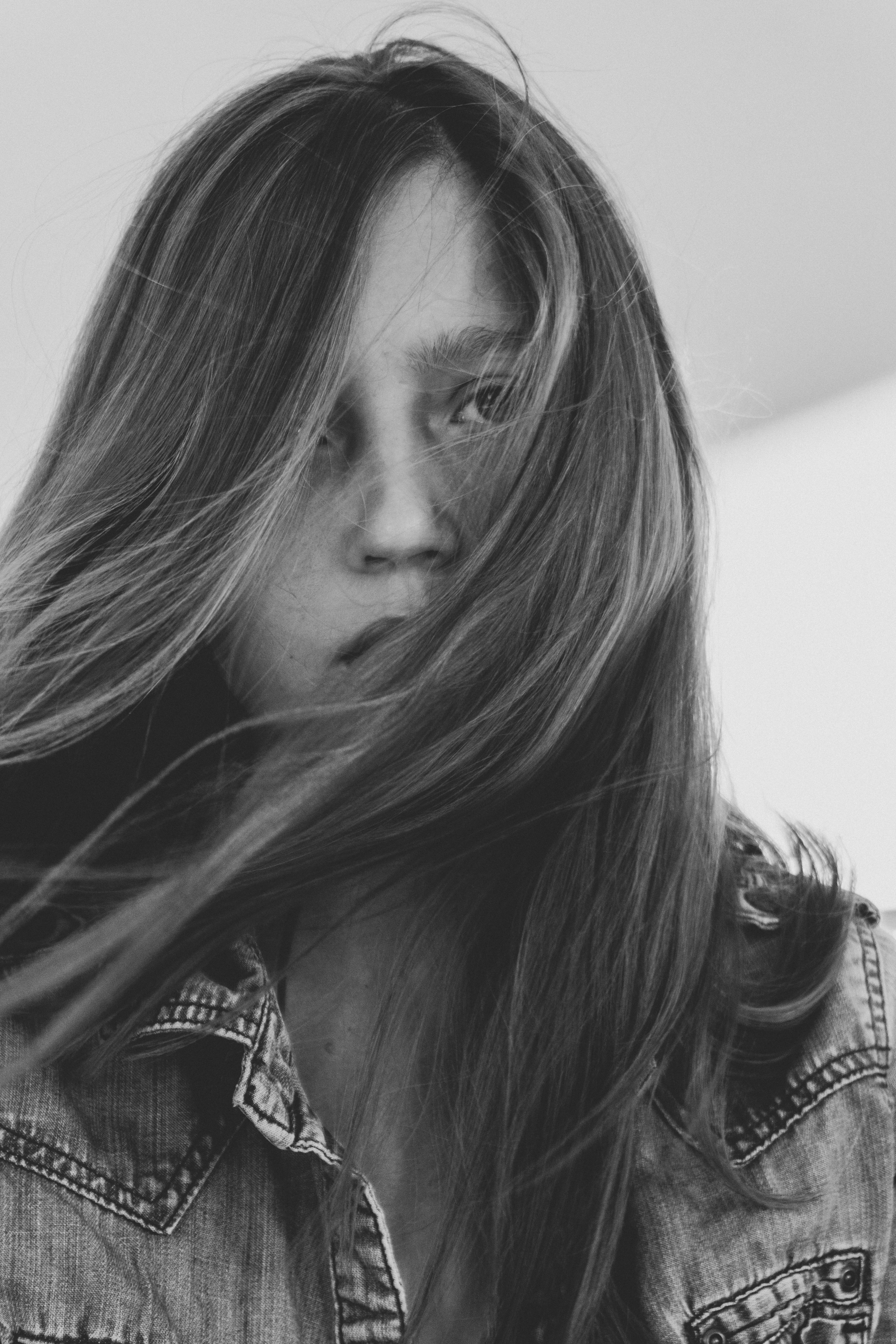 Young Woman in Jacket Posing with Hand Raised Above Head · Free Stock Photo