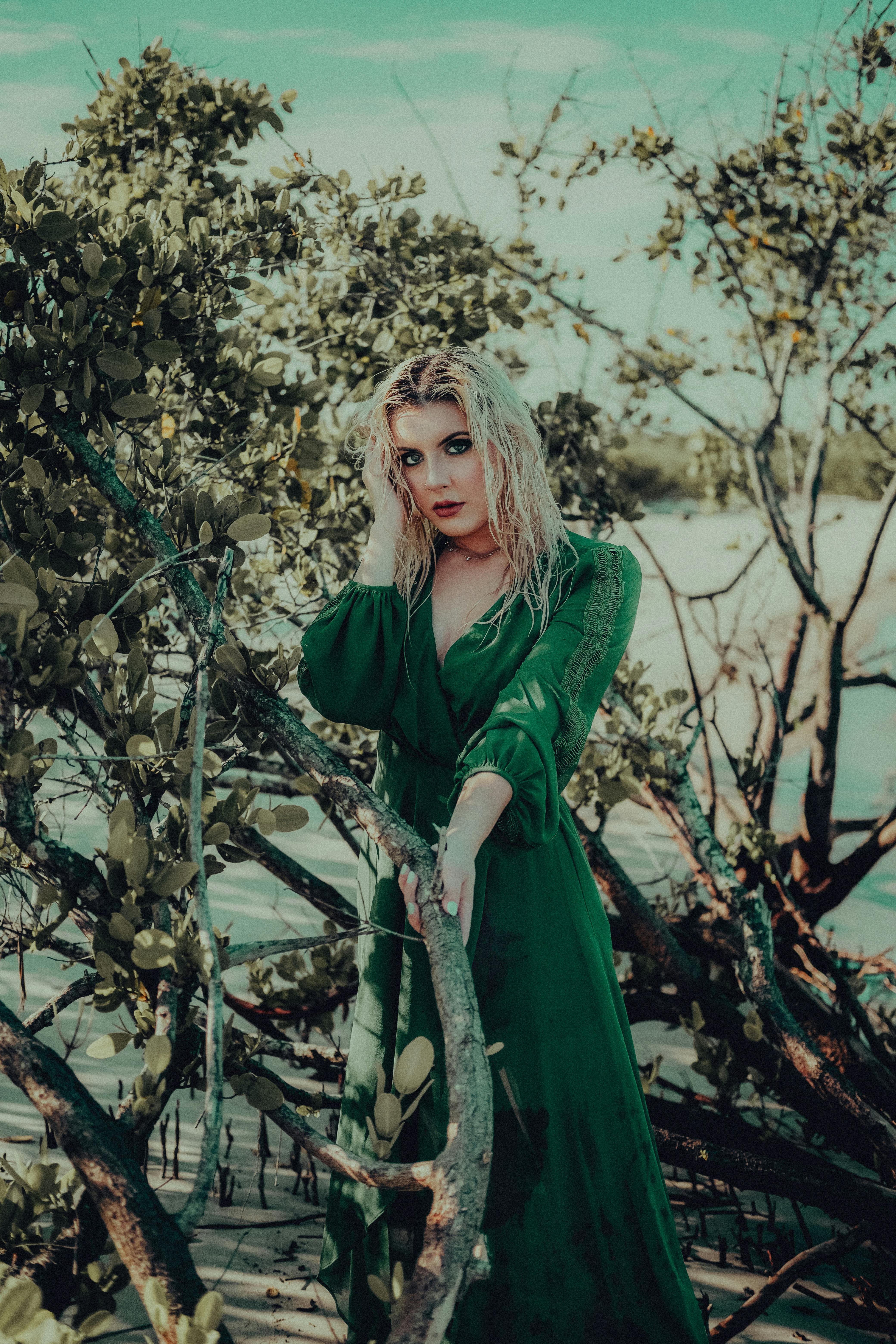 Fixing Hair Blonde Woman in Green Dress in Shrub · Free Stock Photo