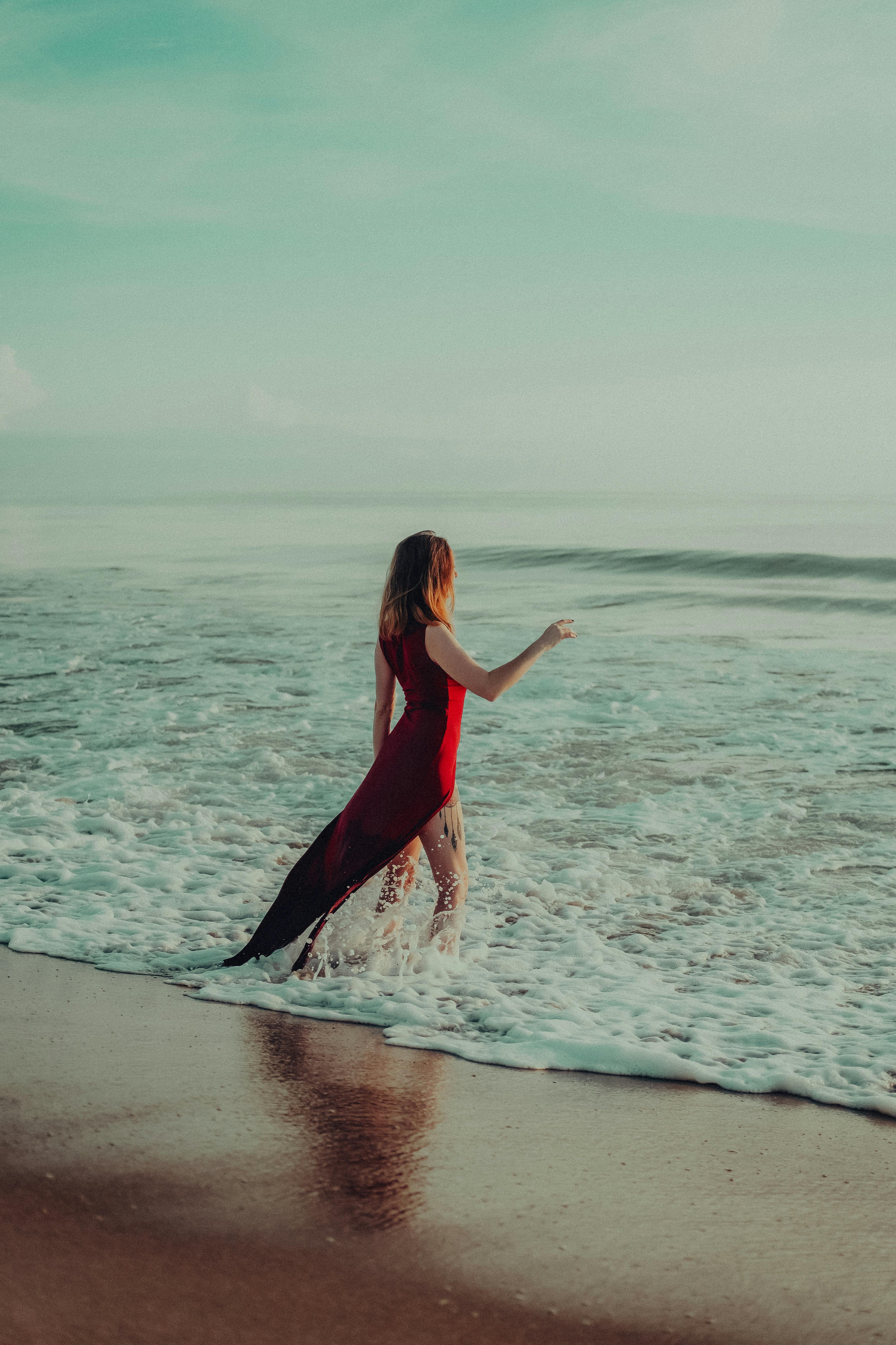 Model in a Red Dress Posing on the Seashore · Free Stock Photo