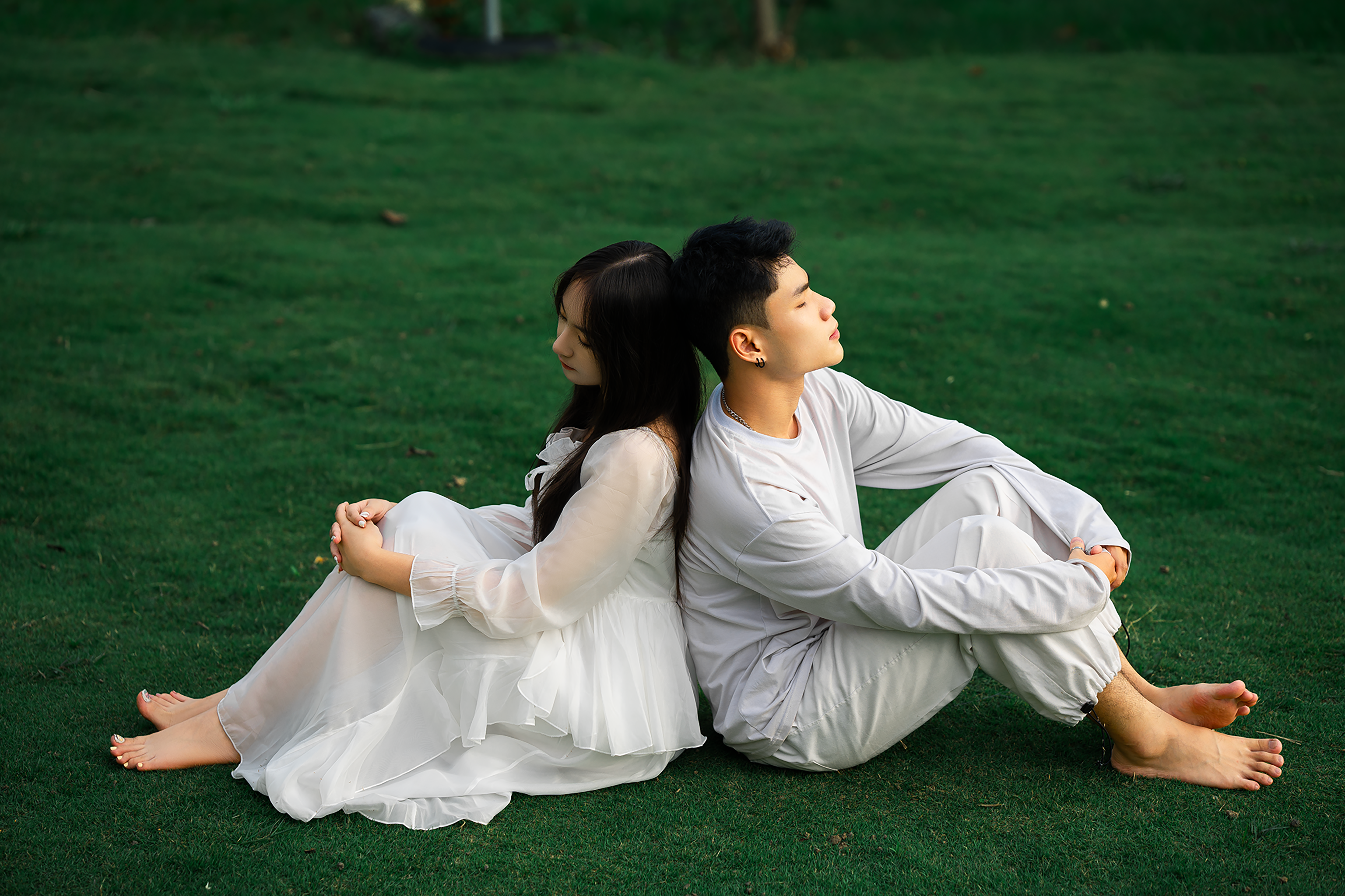 Couple Sitting Back to Back on Grass · Free Stock Photo