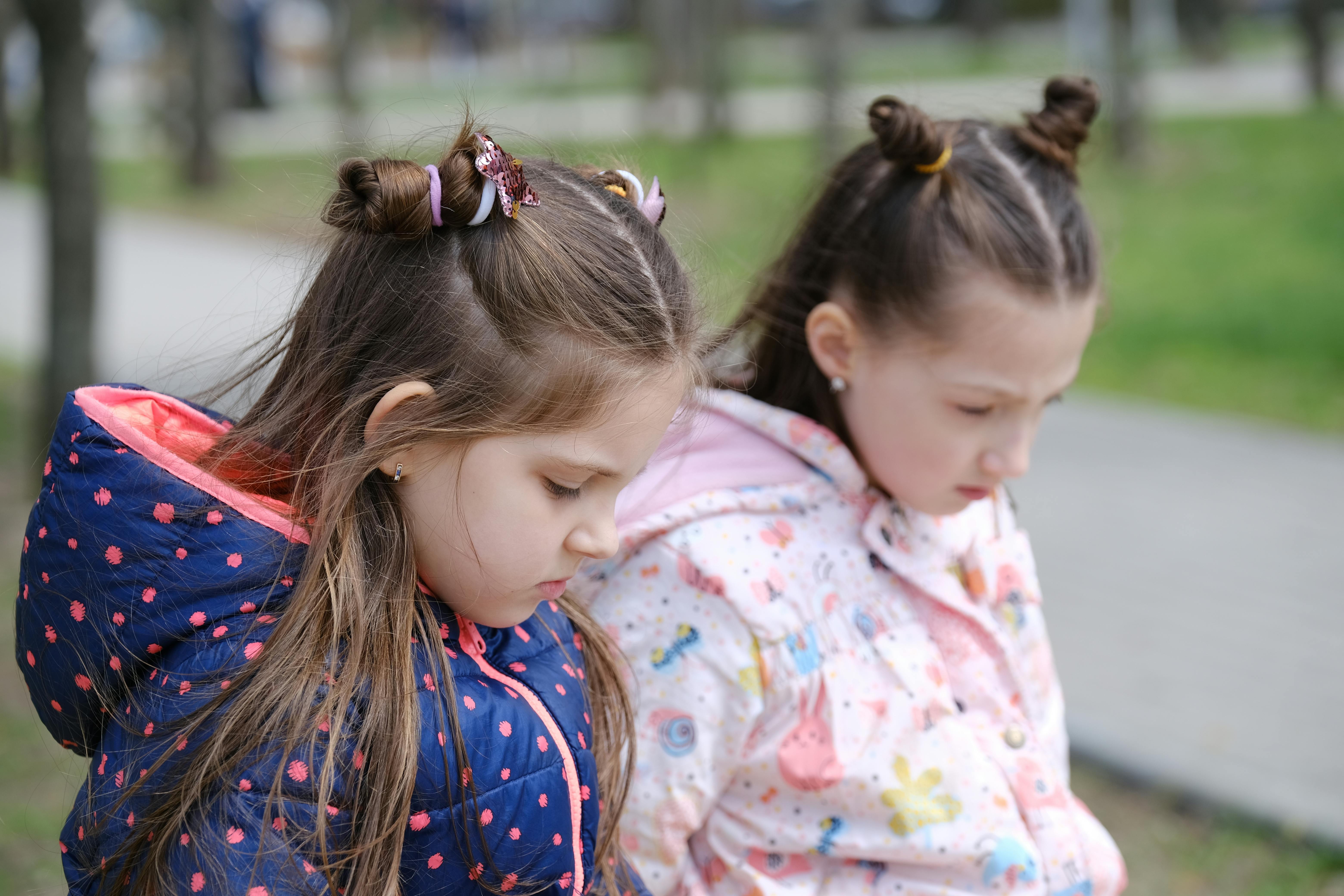 Emotional scene of two adorable girls sitting pensively on a bench ...