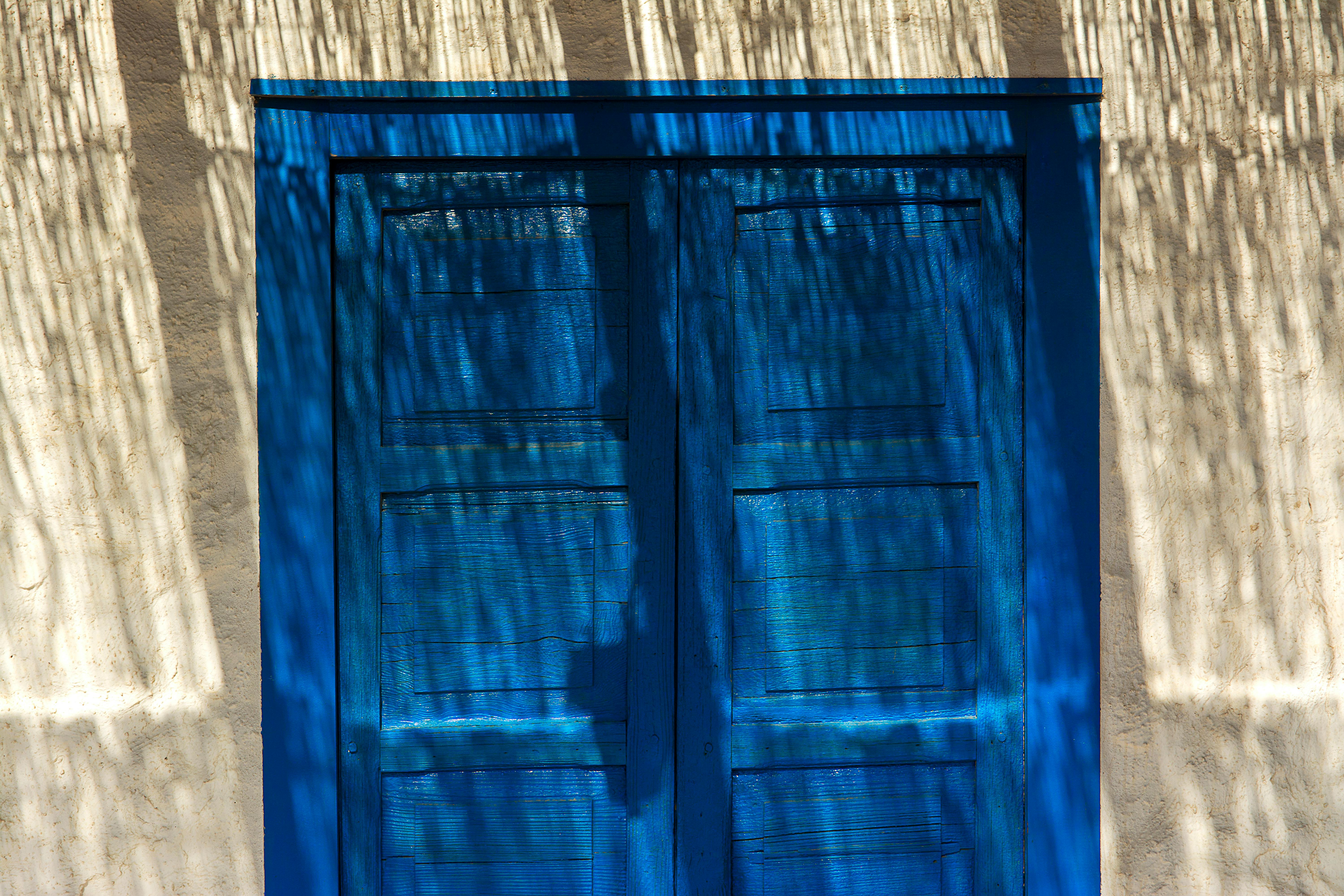 Shadow of a Straw Roof on a Wooden Blue Double Doors · Free Stock Photo
