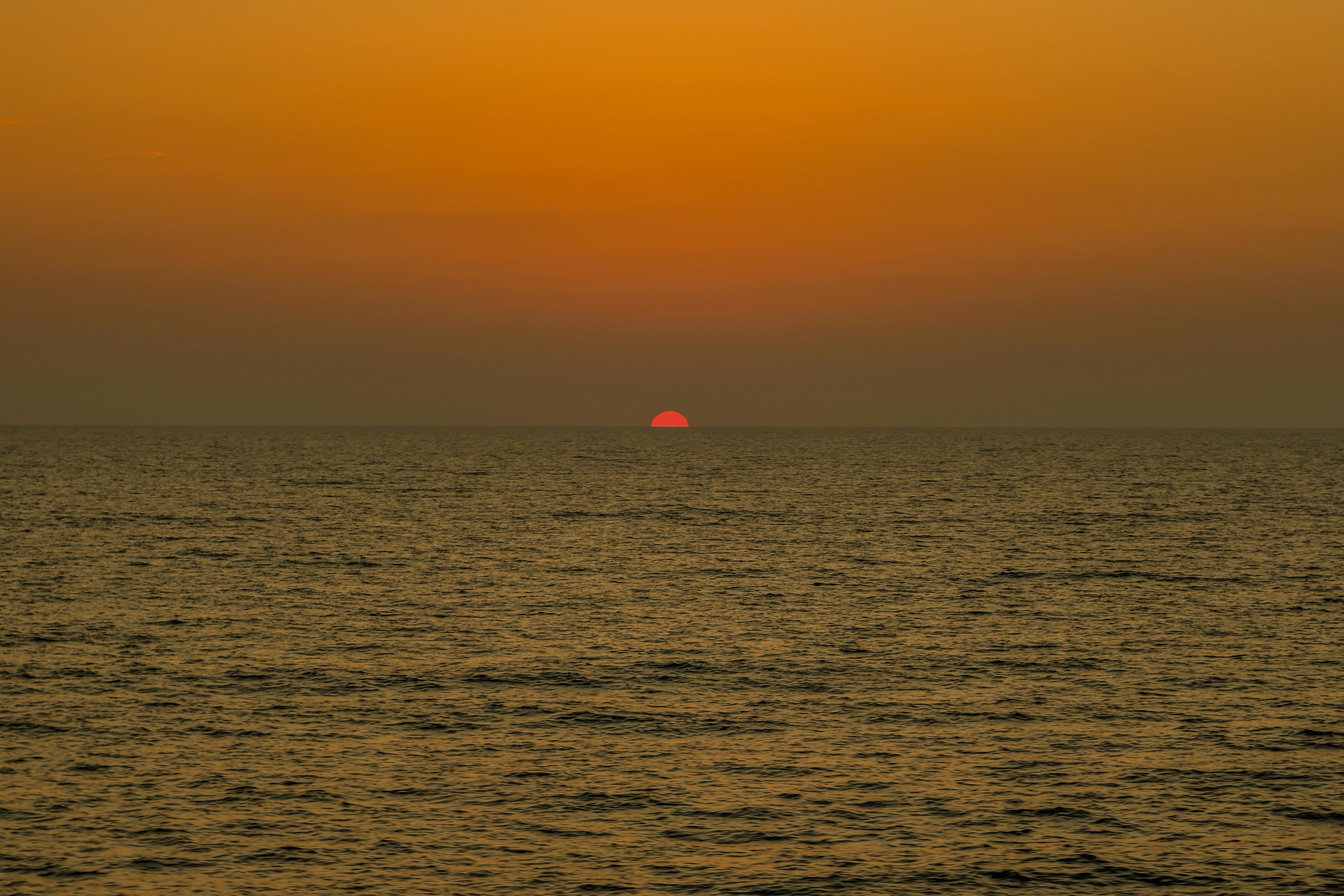 Red Sun Setting behind Ocean · Free Stock Photo
