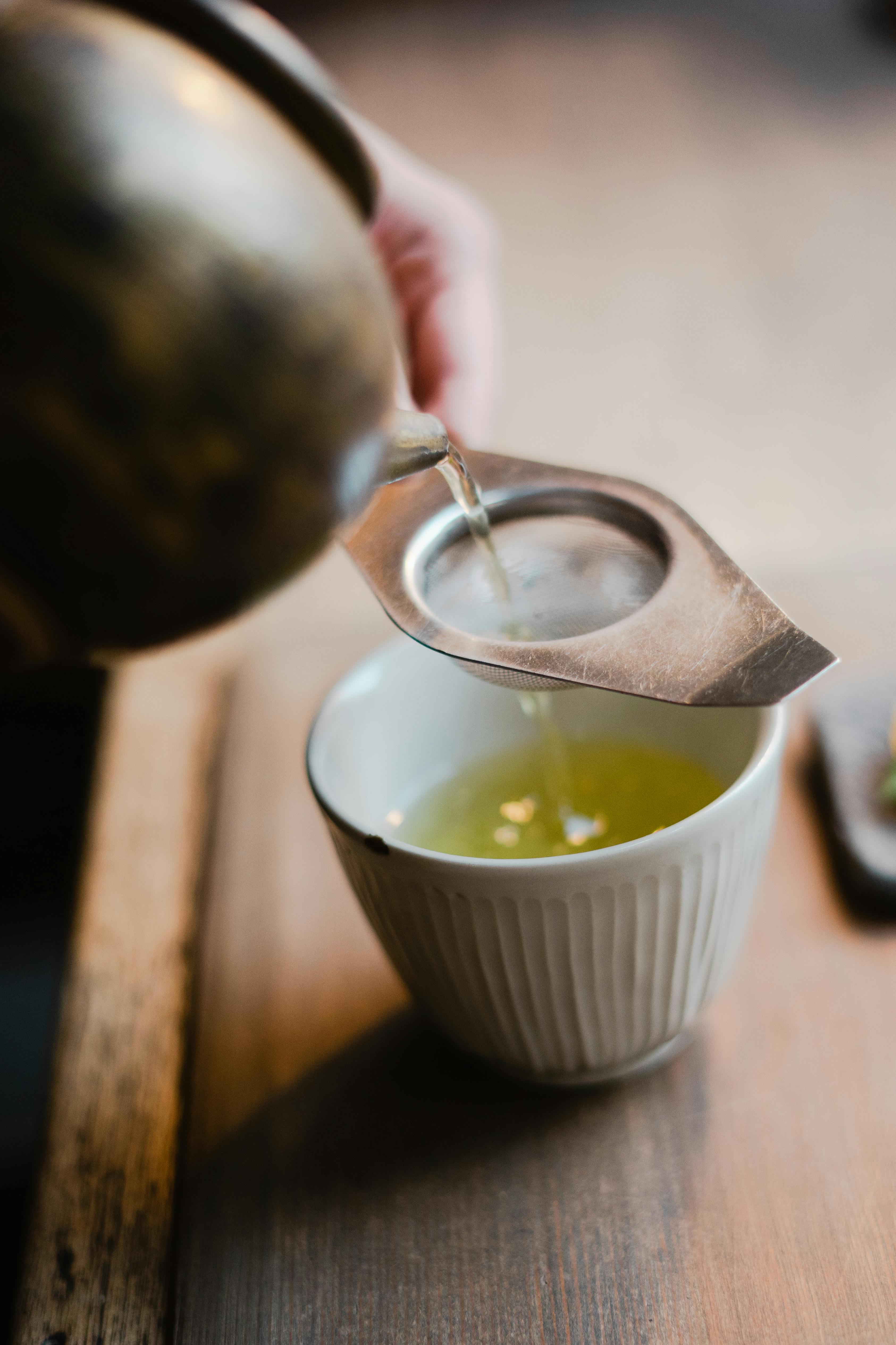 Close-up of Tea Being Poured into a Cup through a Strainer · Free Stock ...