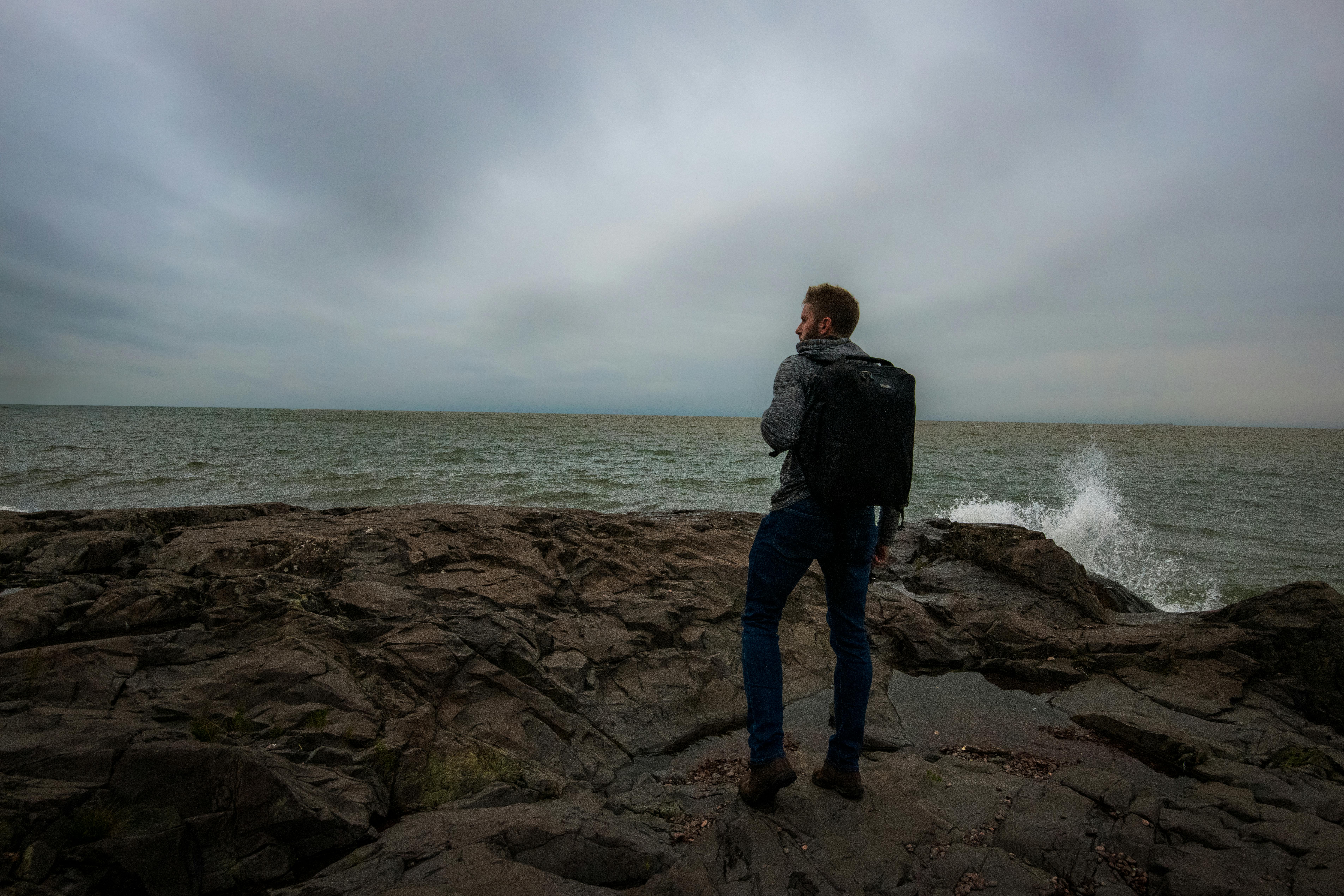 Man Standing on Rocks on Sea Shore · Free Stock Photo