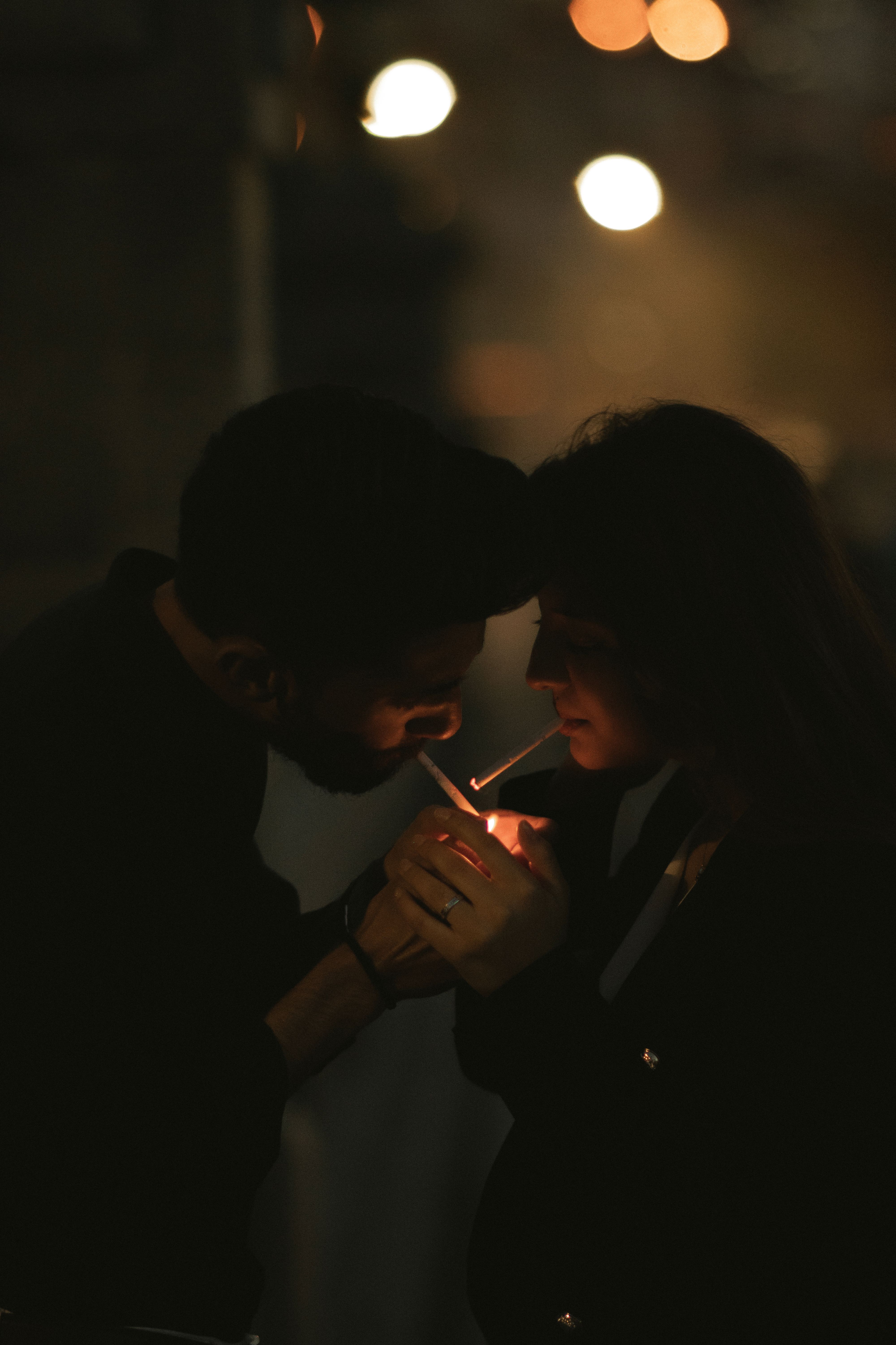 Two People Share a Lighter to Smoke Cigarettes Together · Free Stock Photo
