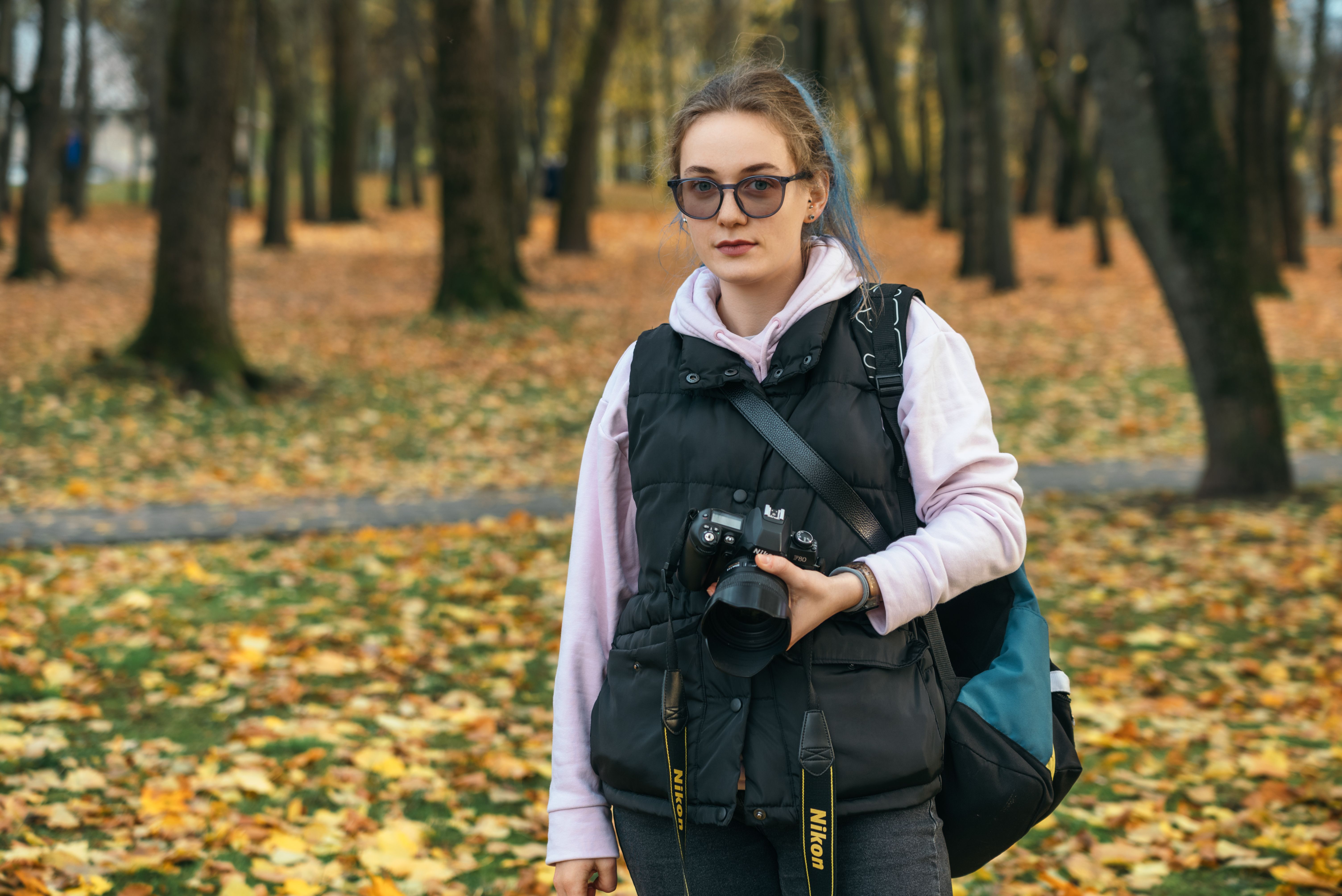 Woman Holding Dslr Camera Sitting on Red Leaved Plant · Free Stock Photo