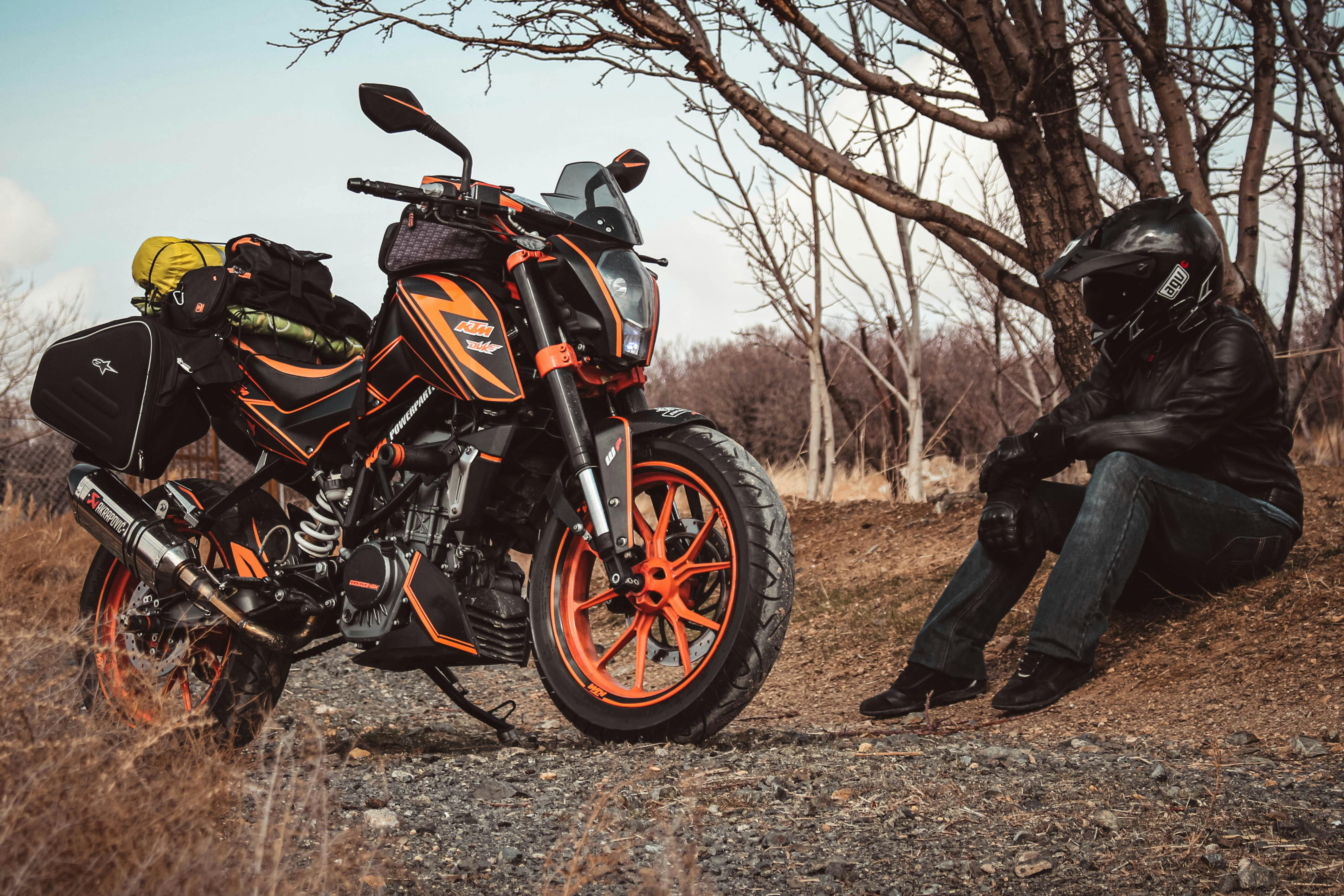 Person Sitting with KTM Motorbike on Footpath · Free Stock Photo