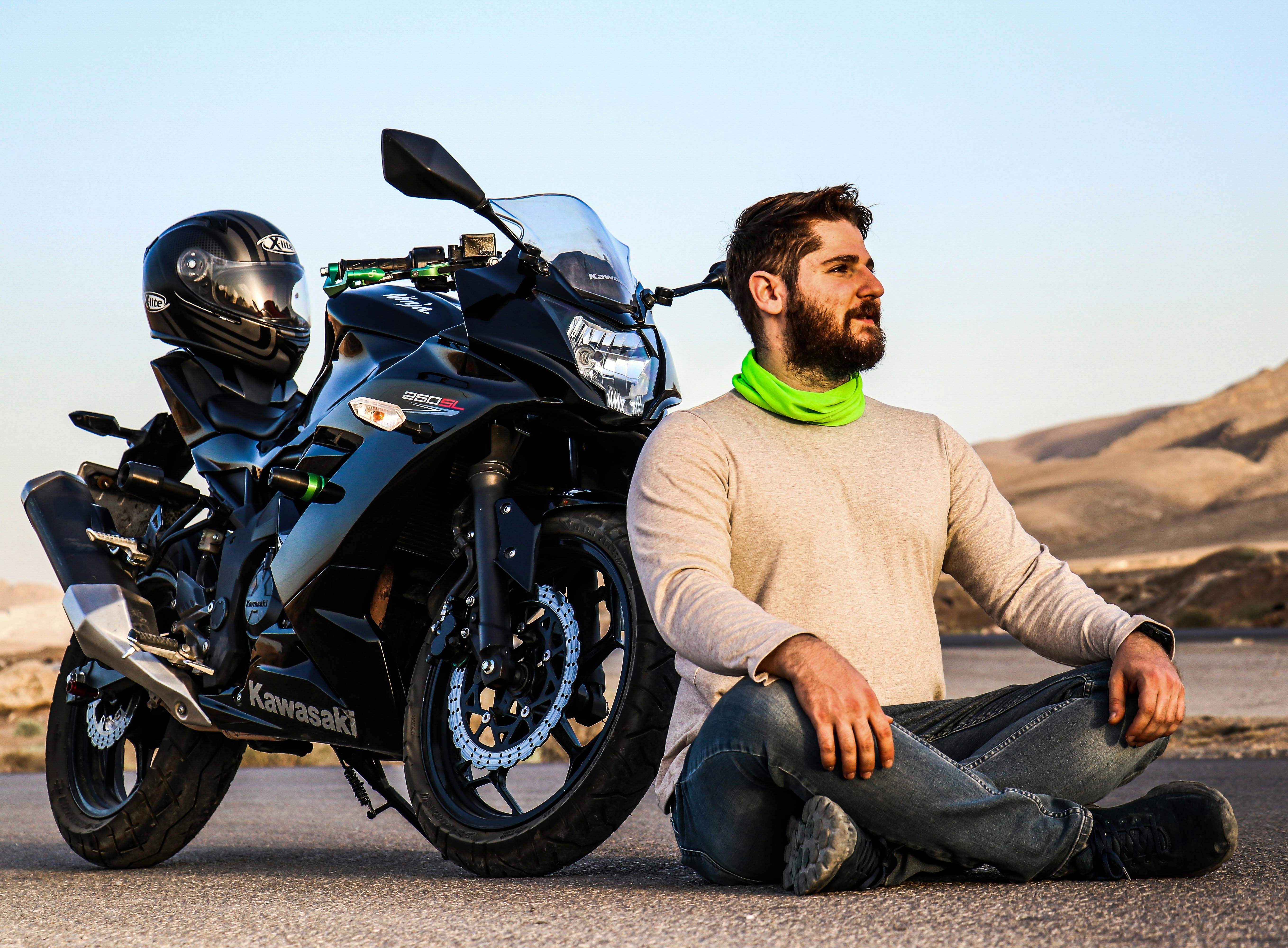 Man Sitting with Kawasaki Motorbike on Road · Free Stock Photo