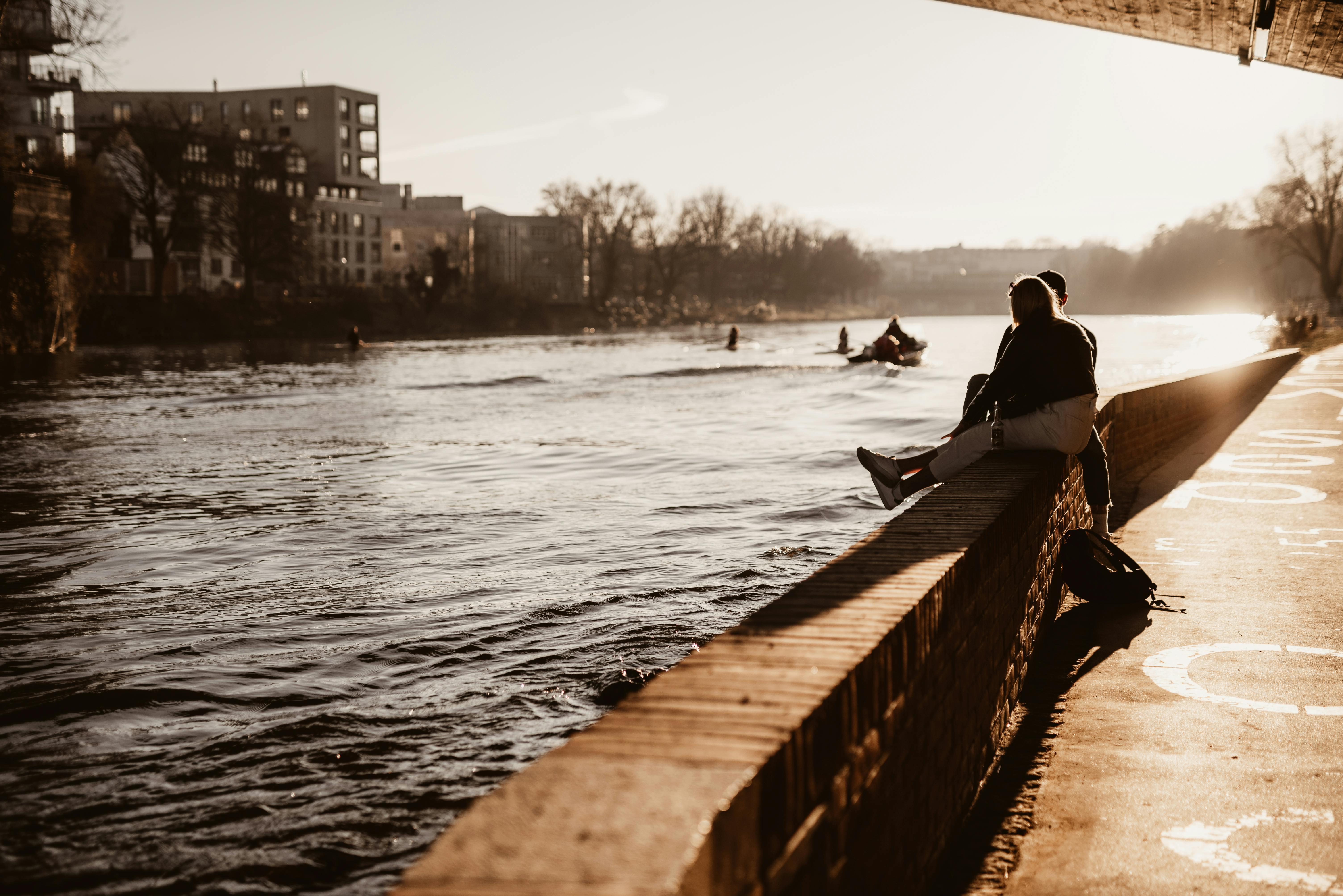 Couple Sitting on the Promenade Wall by the River at Sunset · Free ...