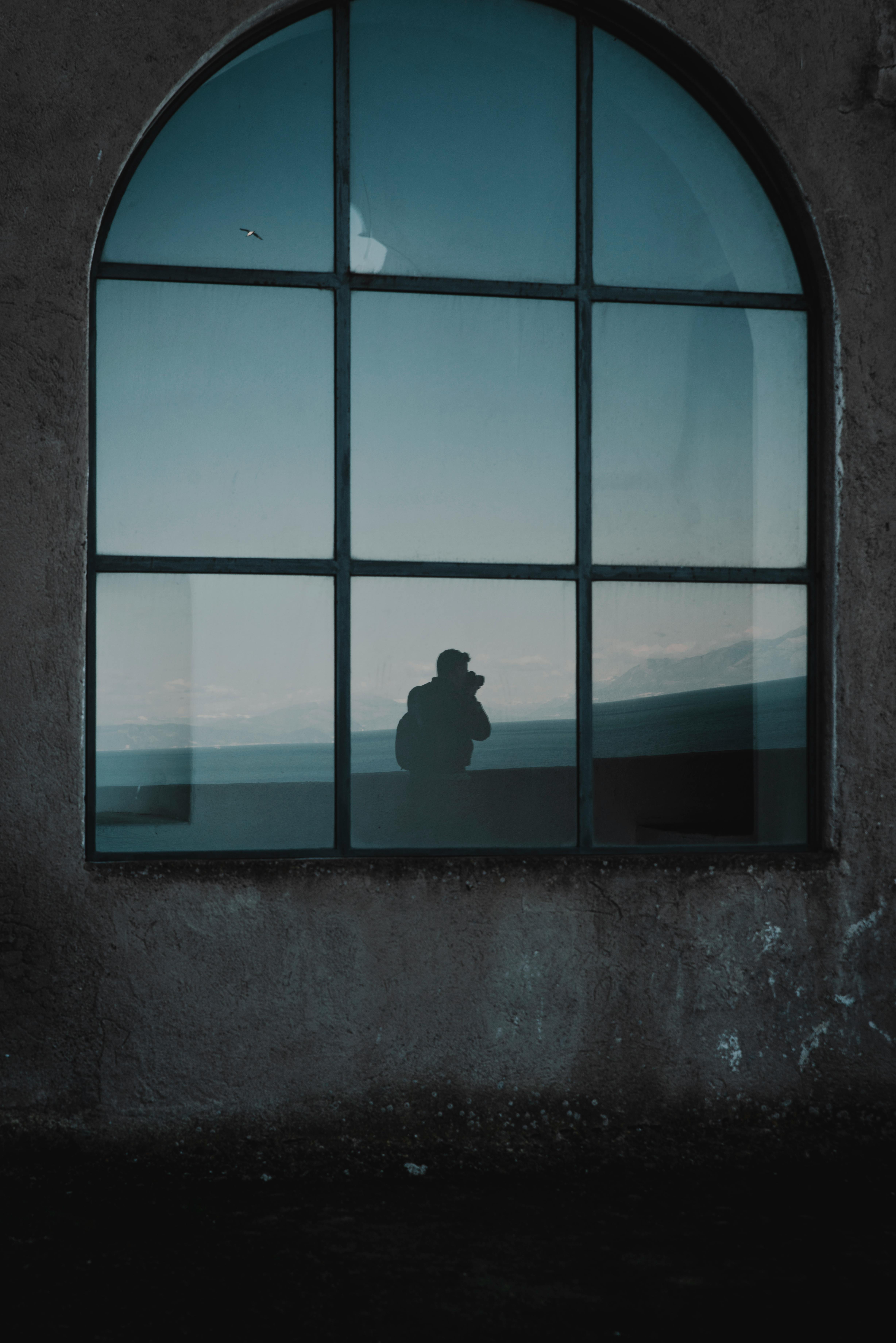 Silhouette Photo of Man Standing Beside Window · Free Stock Photo