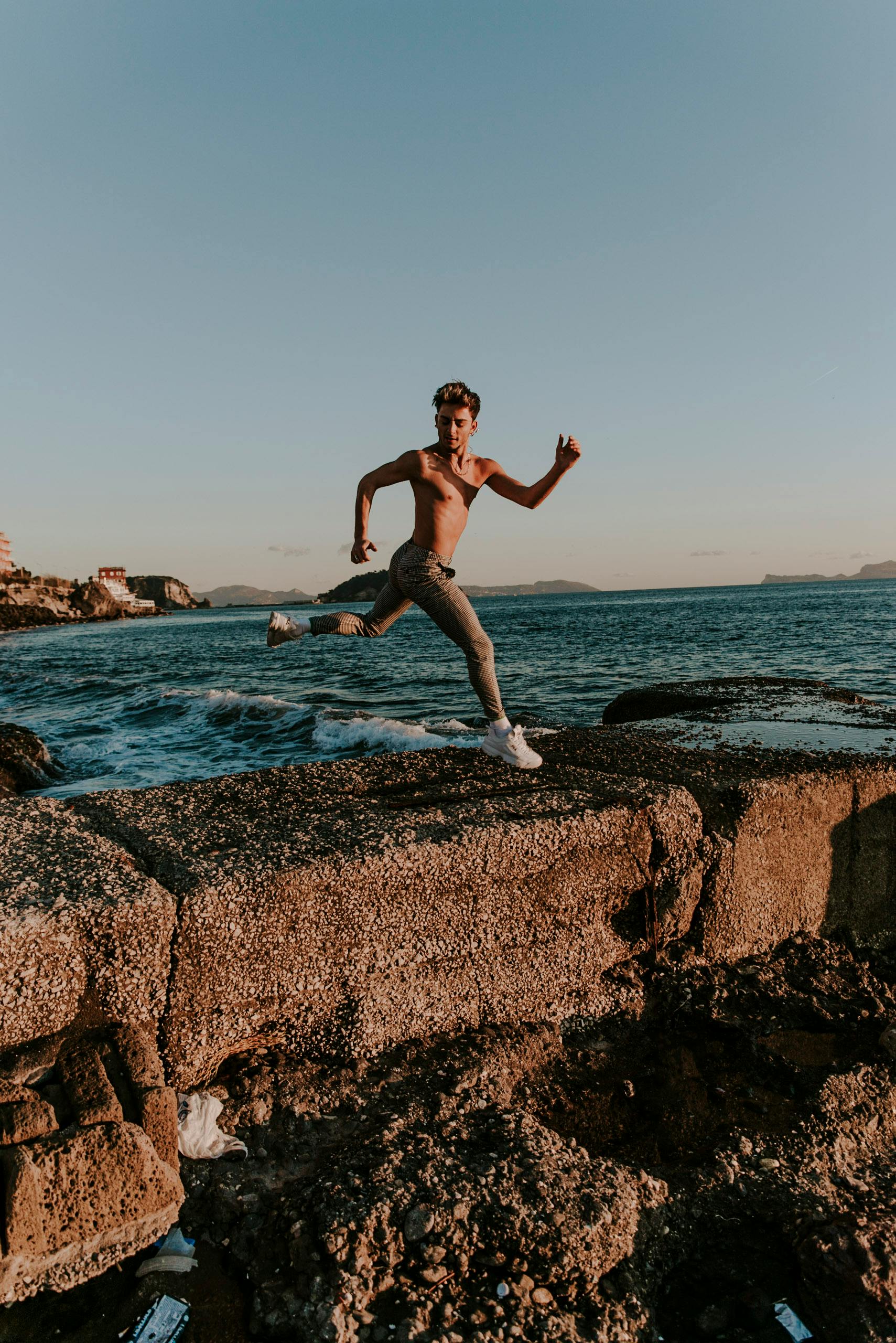 Man Jumping over Brown Barricade Near Shore · Free Stock Photo